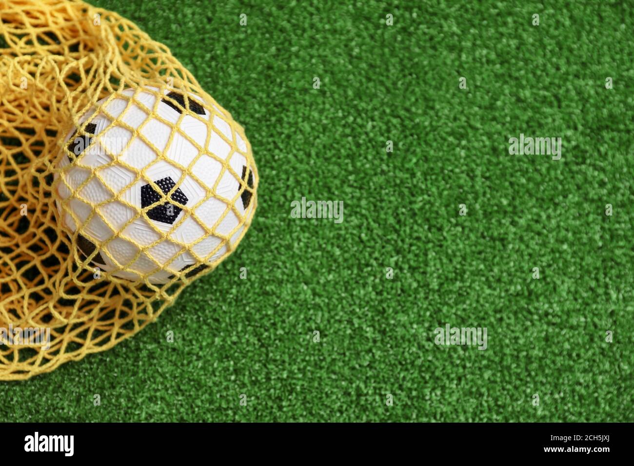 Soccer ball in net on green field Stock Photo - Alamy