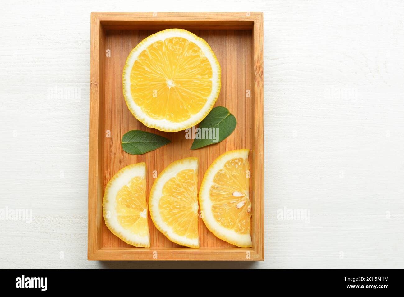 Wooden box with cut lemon on white background Stock Photo - Alamy