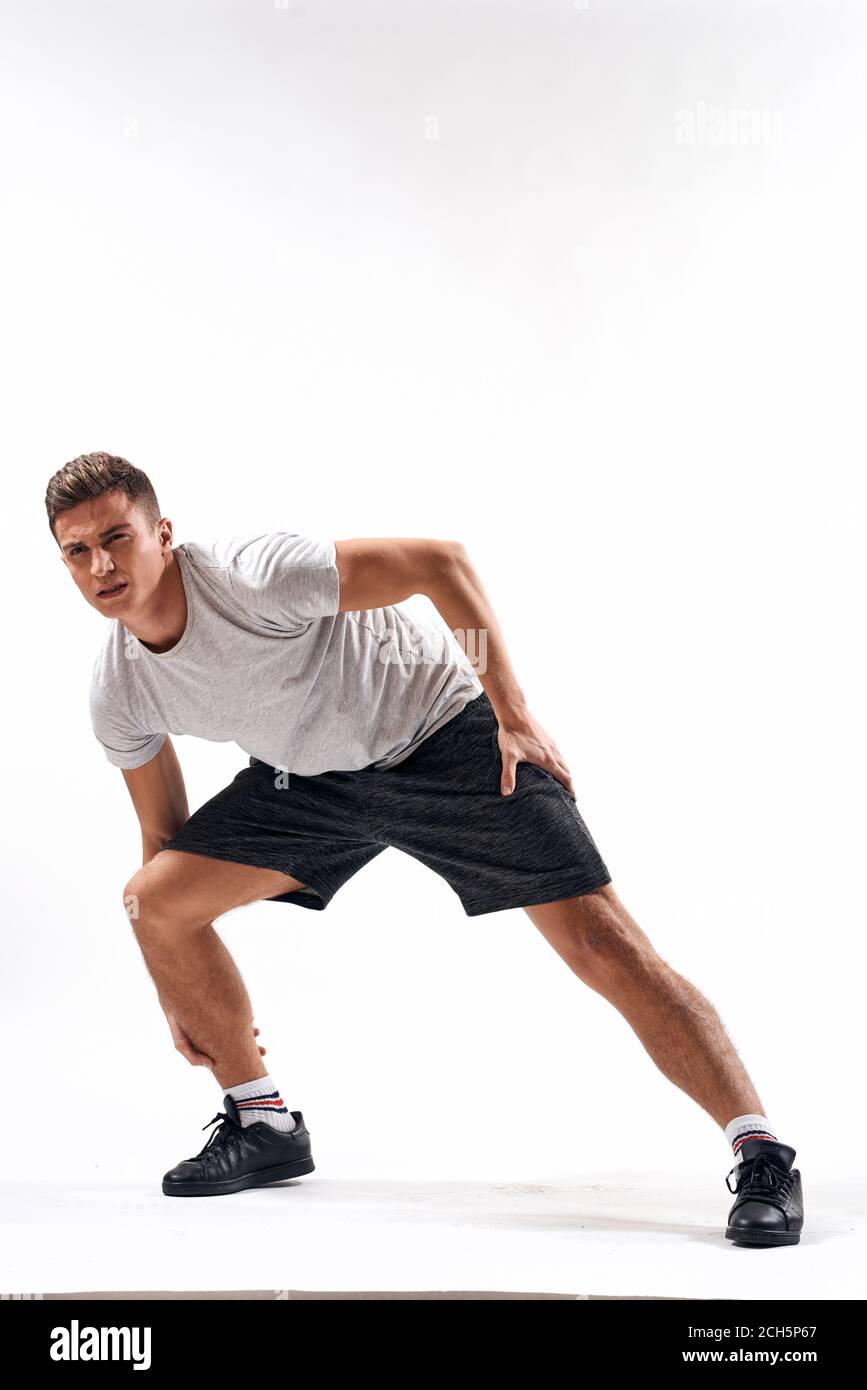 A sports man in shorts and a full-length T-shirt does exercises on a ...