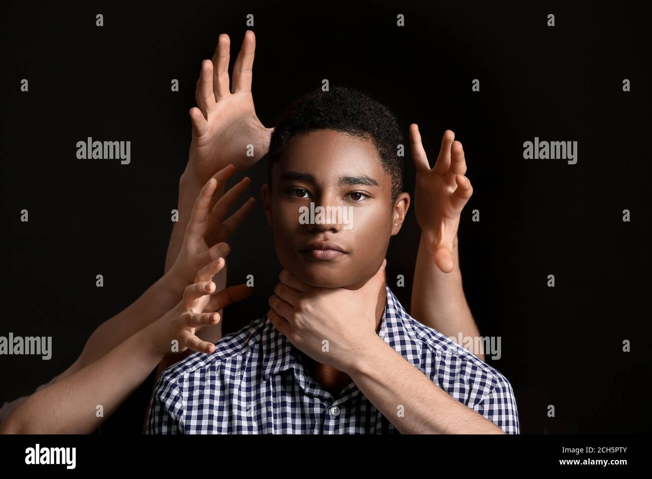 People strangling African-American teenage boy on dark background. Stop ...