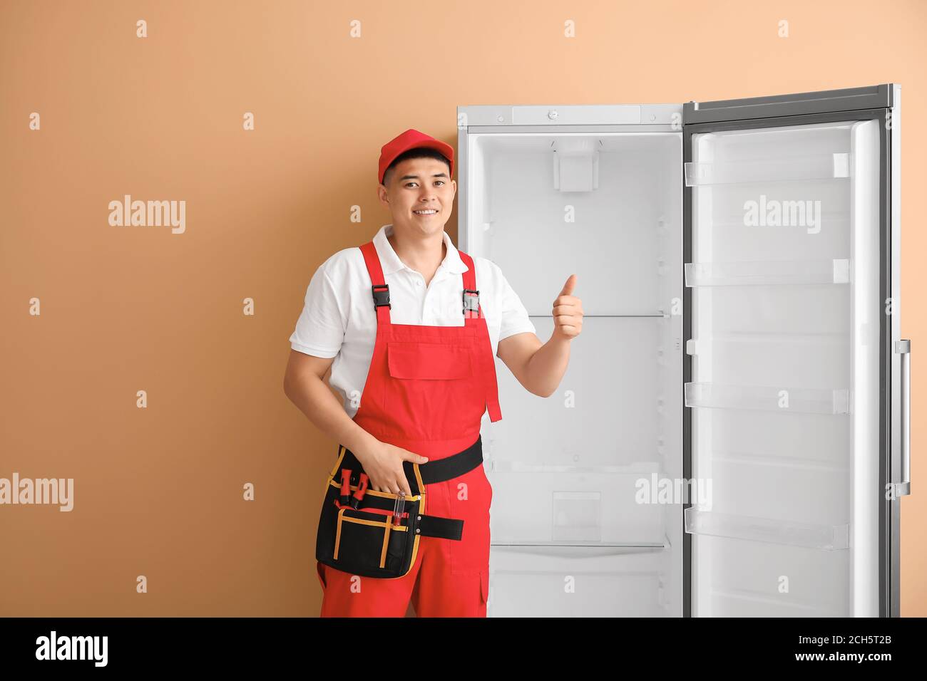 Worker of repair service near fridge on color background Stock Photo ...