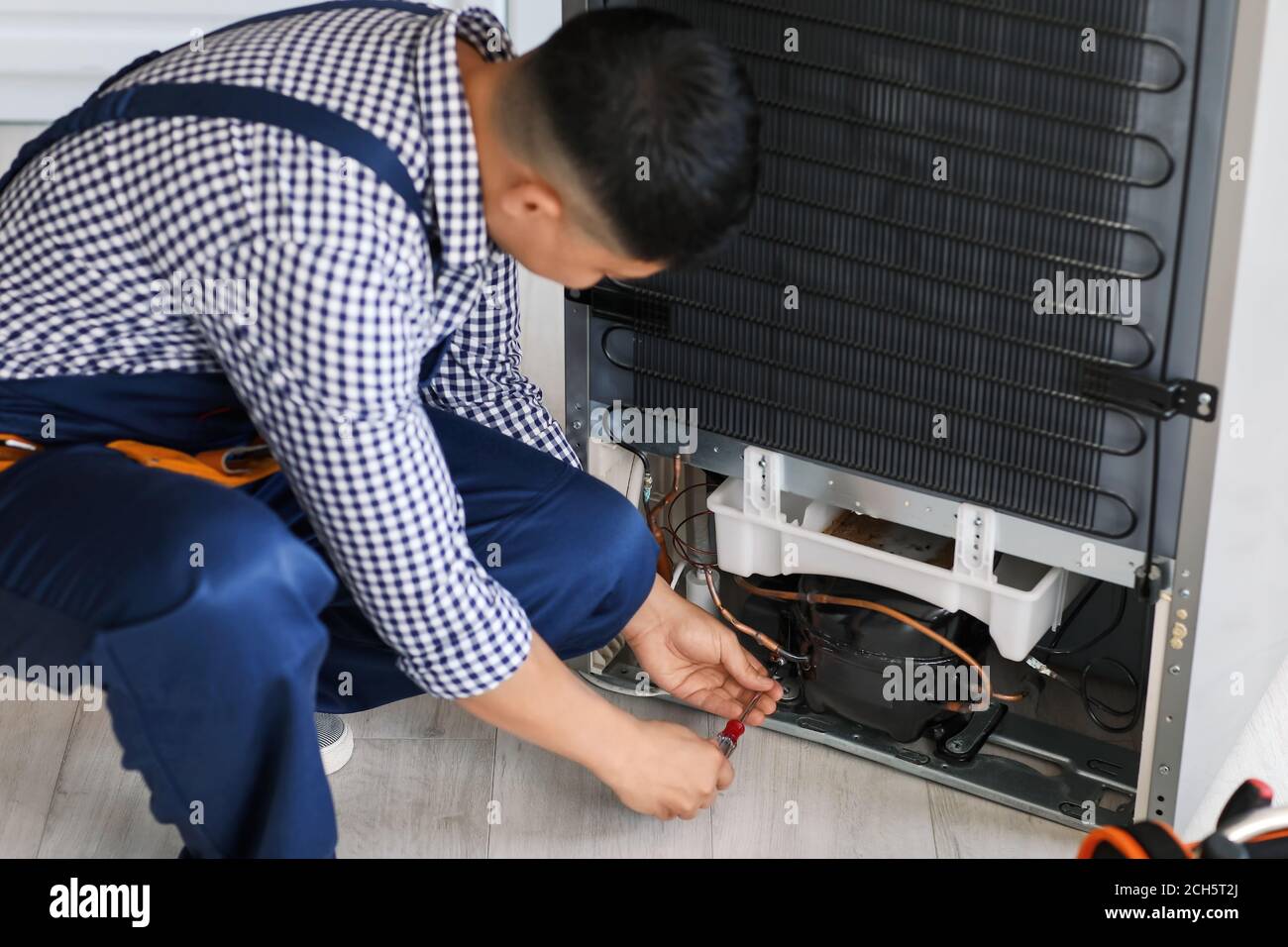 Worker repairing fridge in kitchen Stock Photo - Alamy