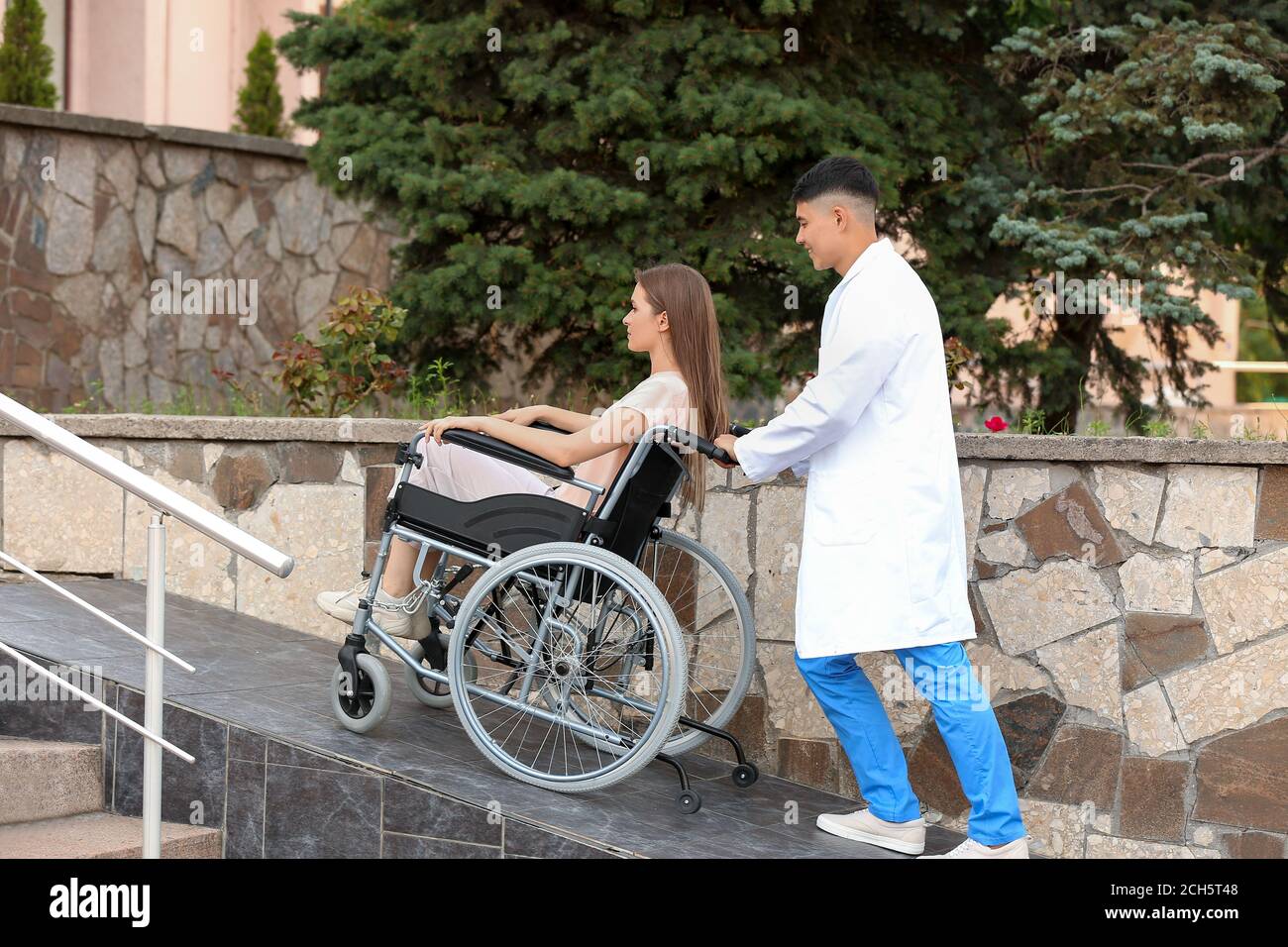 Doctor and young woman in wheelchair on ramp outdoors Stock Photo - Alamy