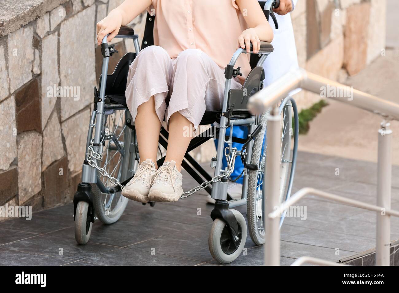Doctor and young woman in wheelchair on ramp outdoors Stock Photo - Alamy
