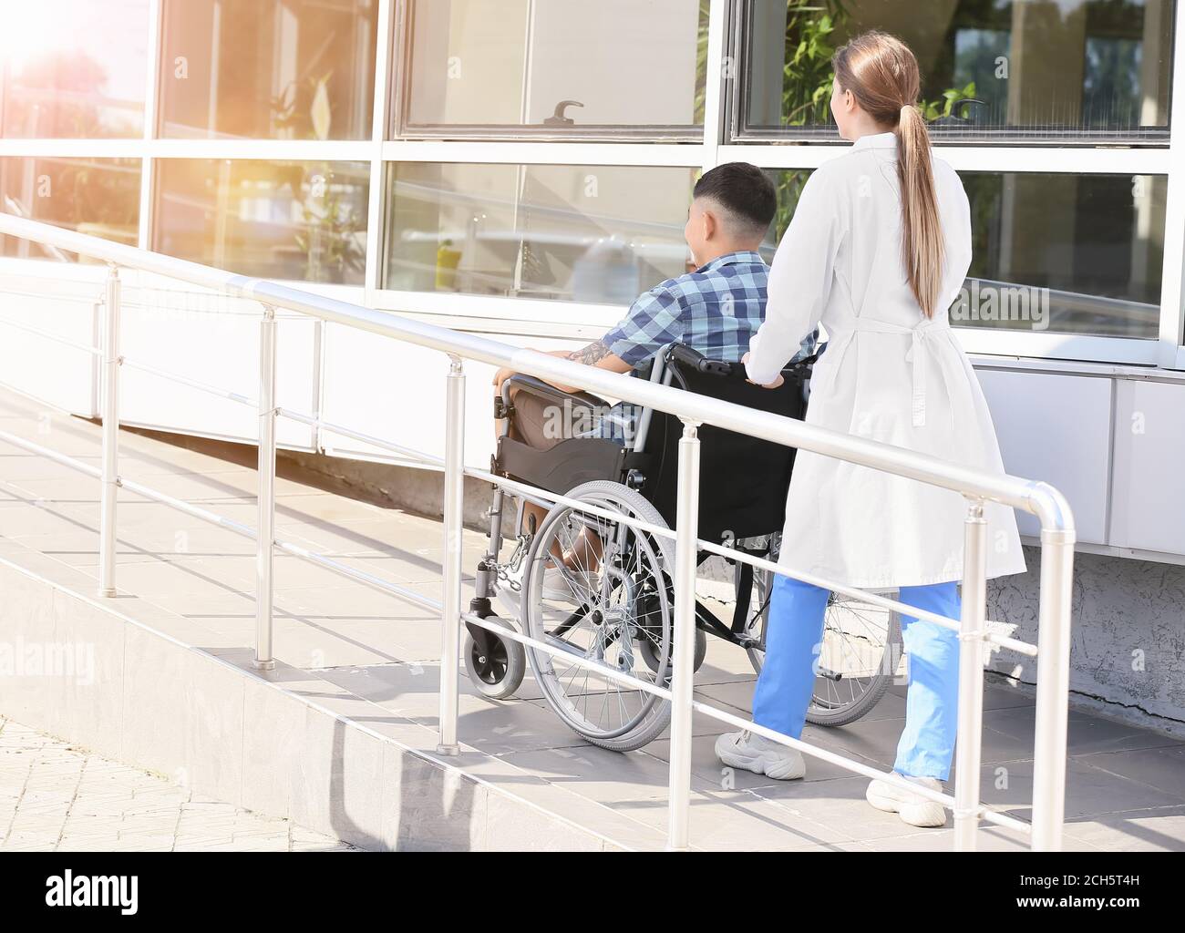 Doctor and young man in wheelchair on ramp outdoors Stock Photo - Alamy