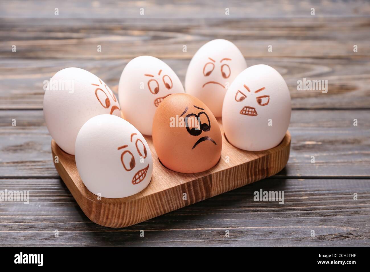 Chicken eggs with drawn faces on wooden background. Racism concept ...