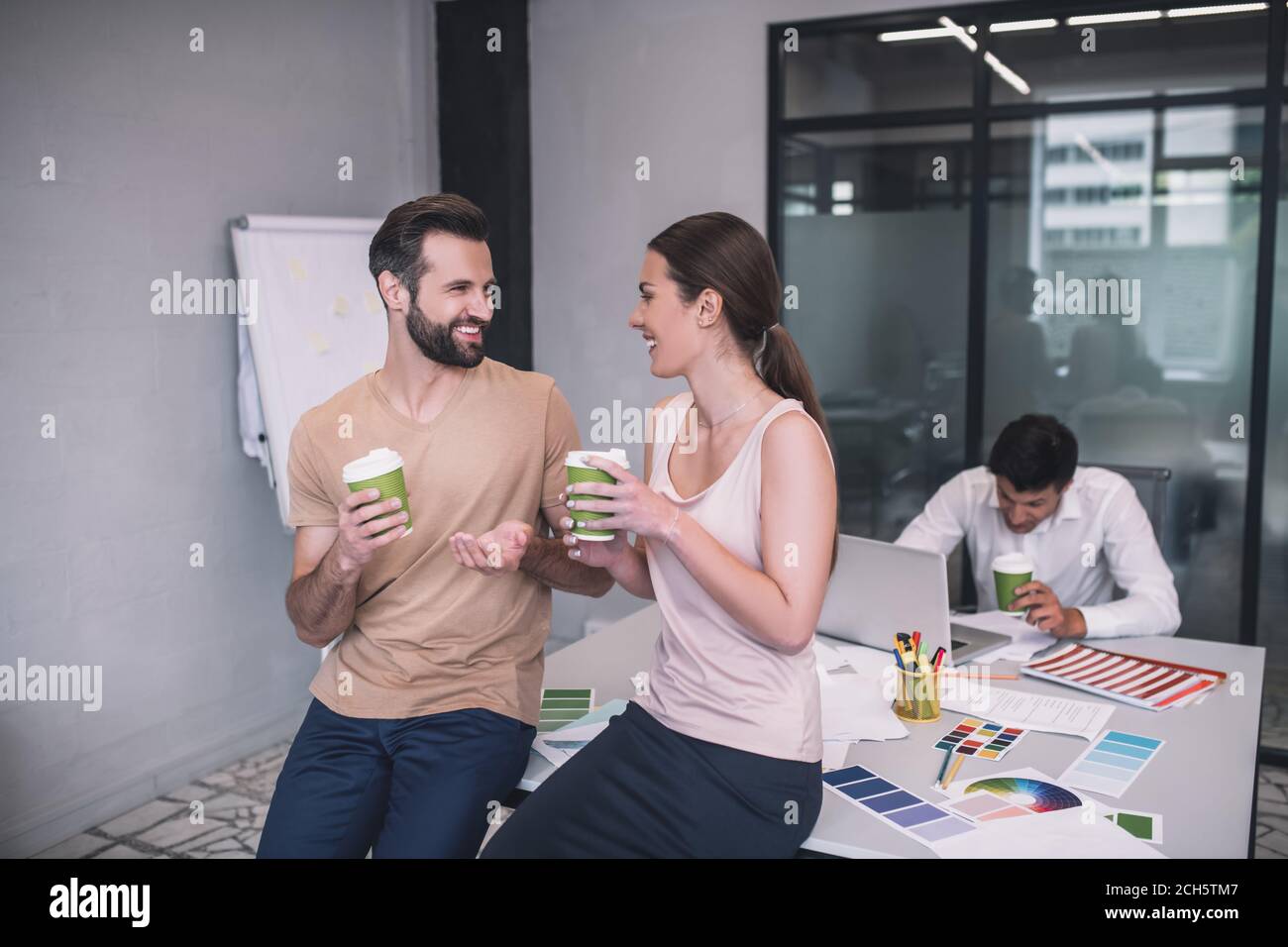 Bearded male and brown-haired female coworkers drinking coffee, their ...