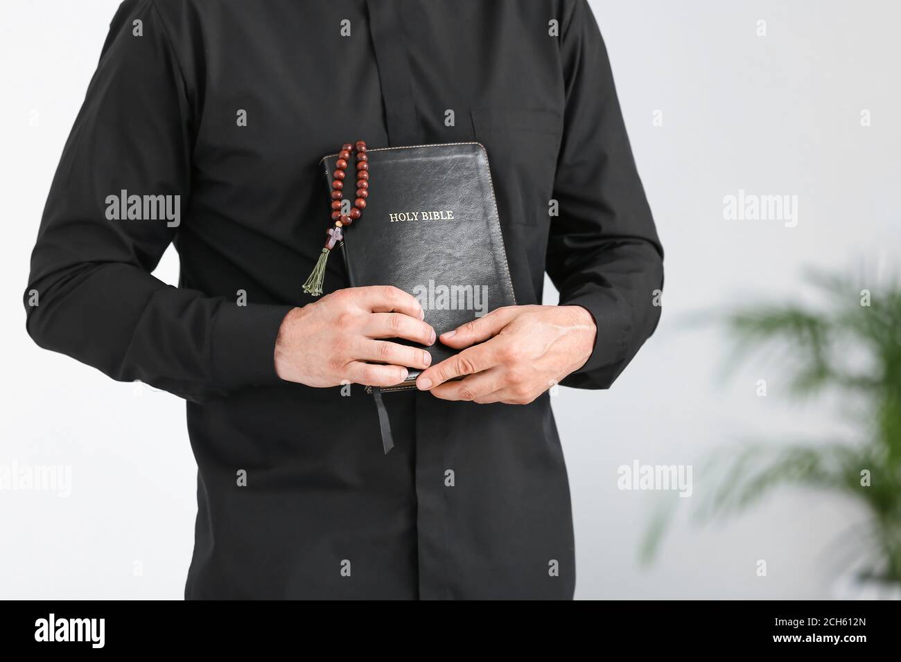 Male priest with Bible at home Stock Photo - Alamy