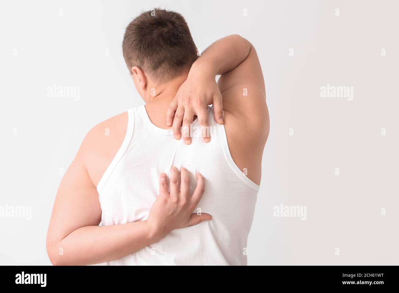 Teenage boy suffering from itching on light background Stock Photo - Alamy