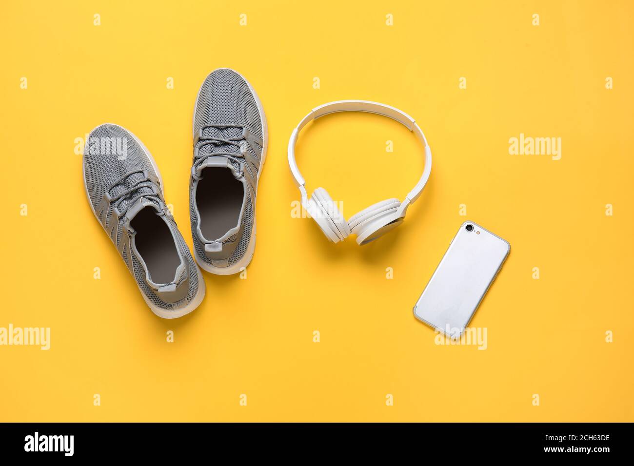 Sportive shoes, mobile phone and headphones on color background Stock ...