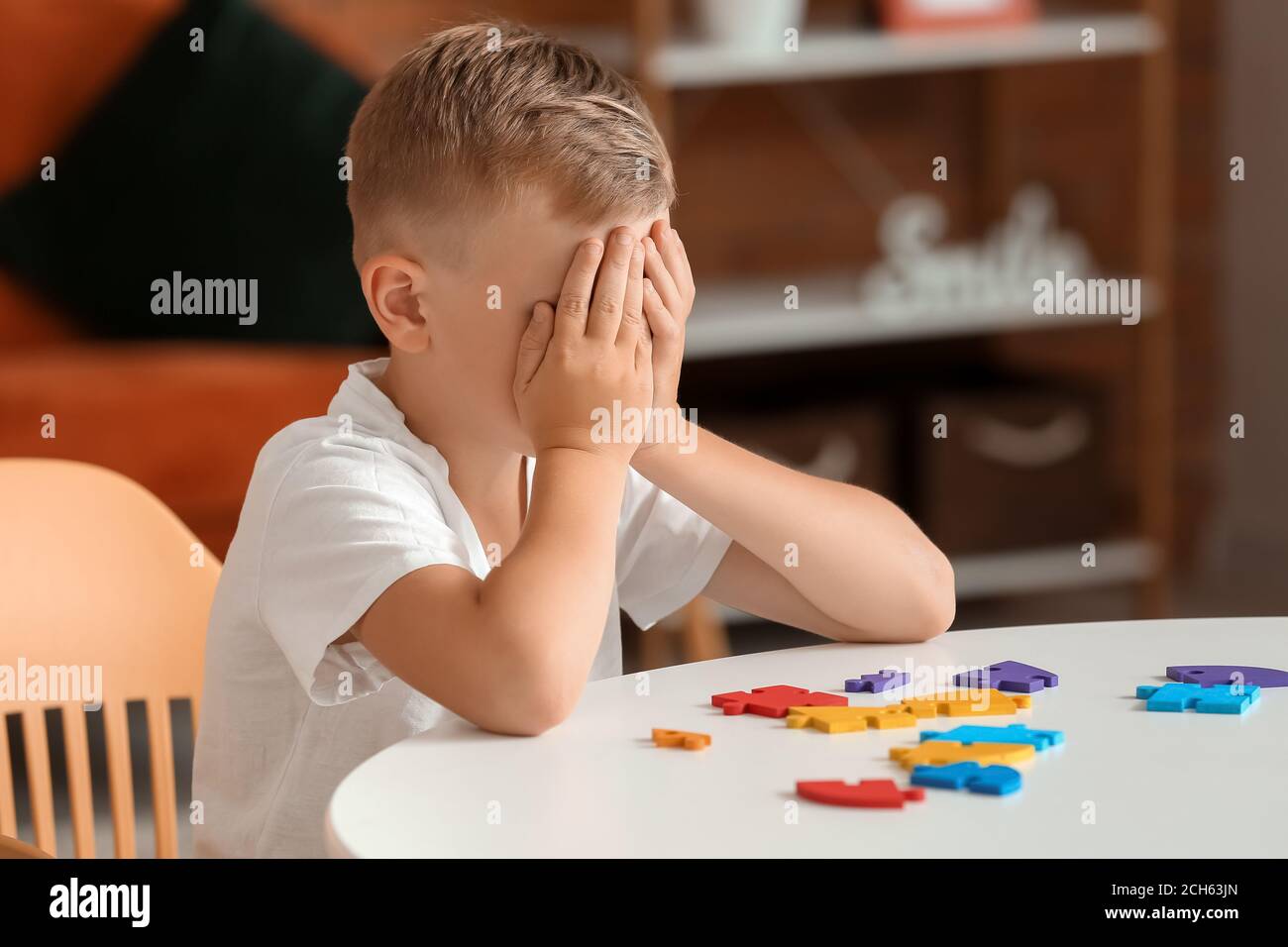 Sad little boy with autistic disorder doing puzzle at home Stock Photo ...