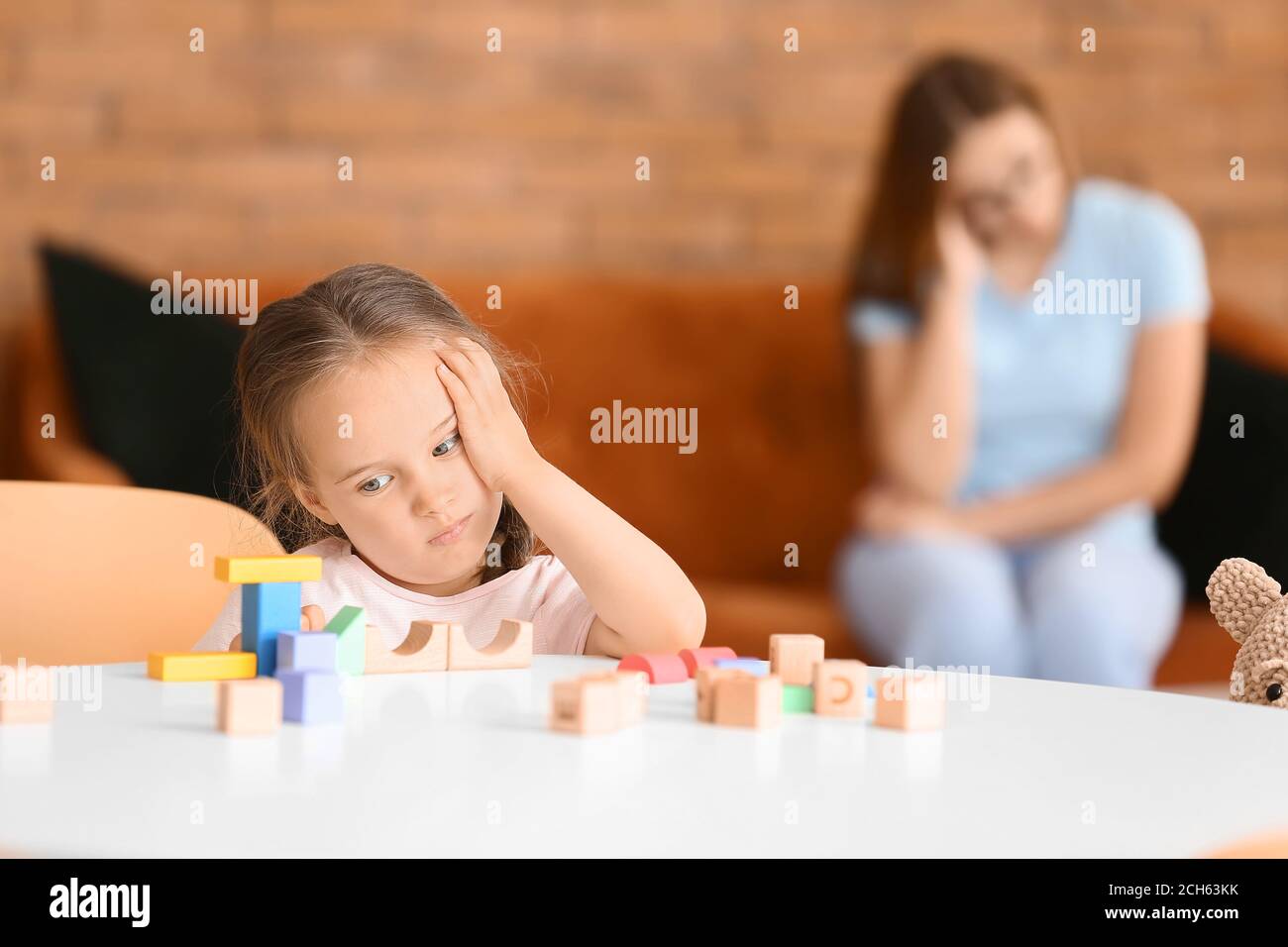 Sad little girl with autistic disorder playing with blocks at home ...