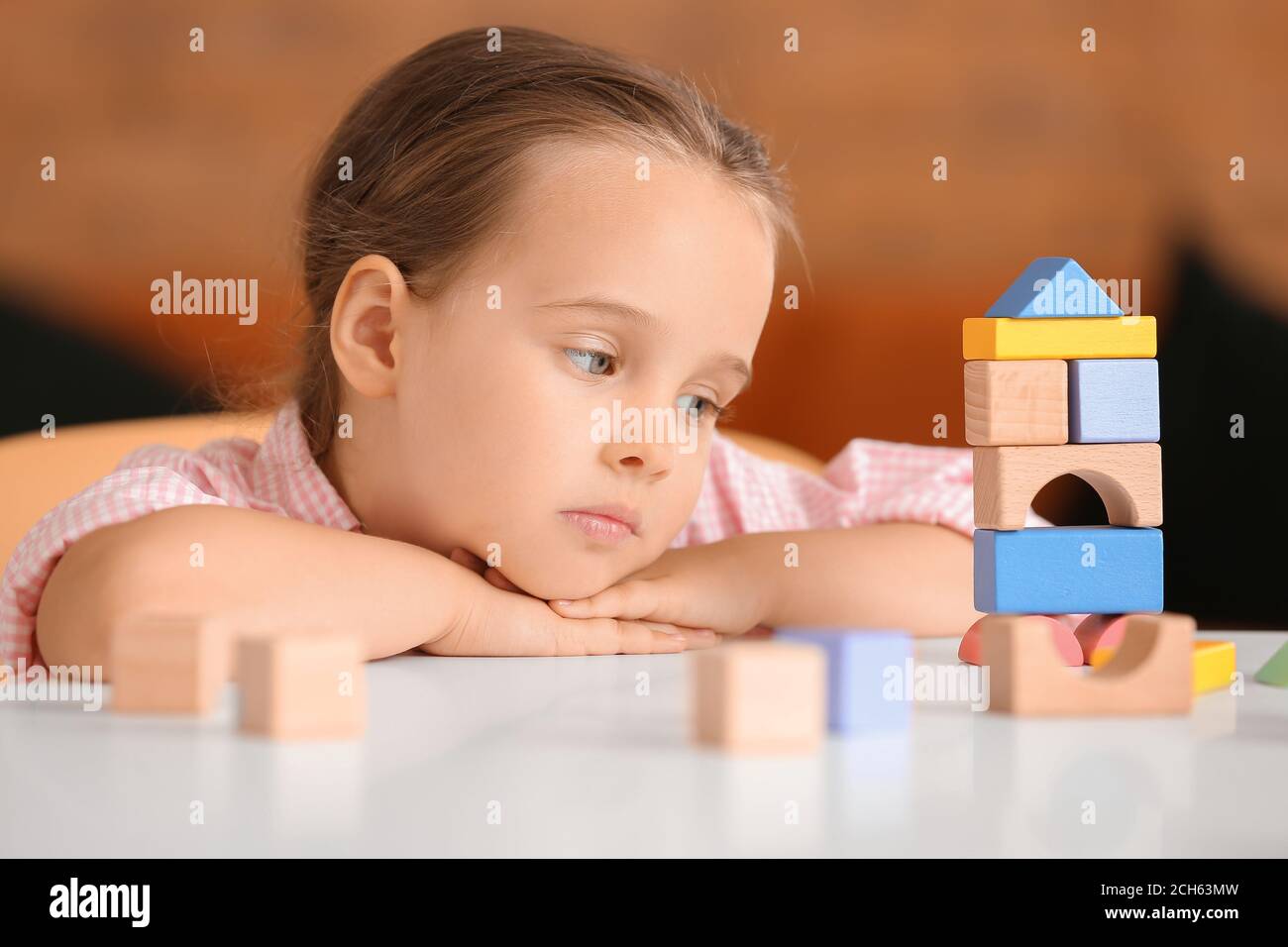 Sad little girl with autistic disorder playing with blocks at home ...