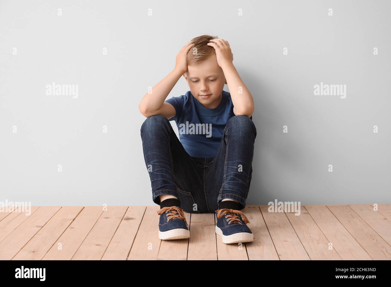 Sad little boy with autistic disorder sitting near light wall Stock ...