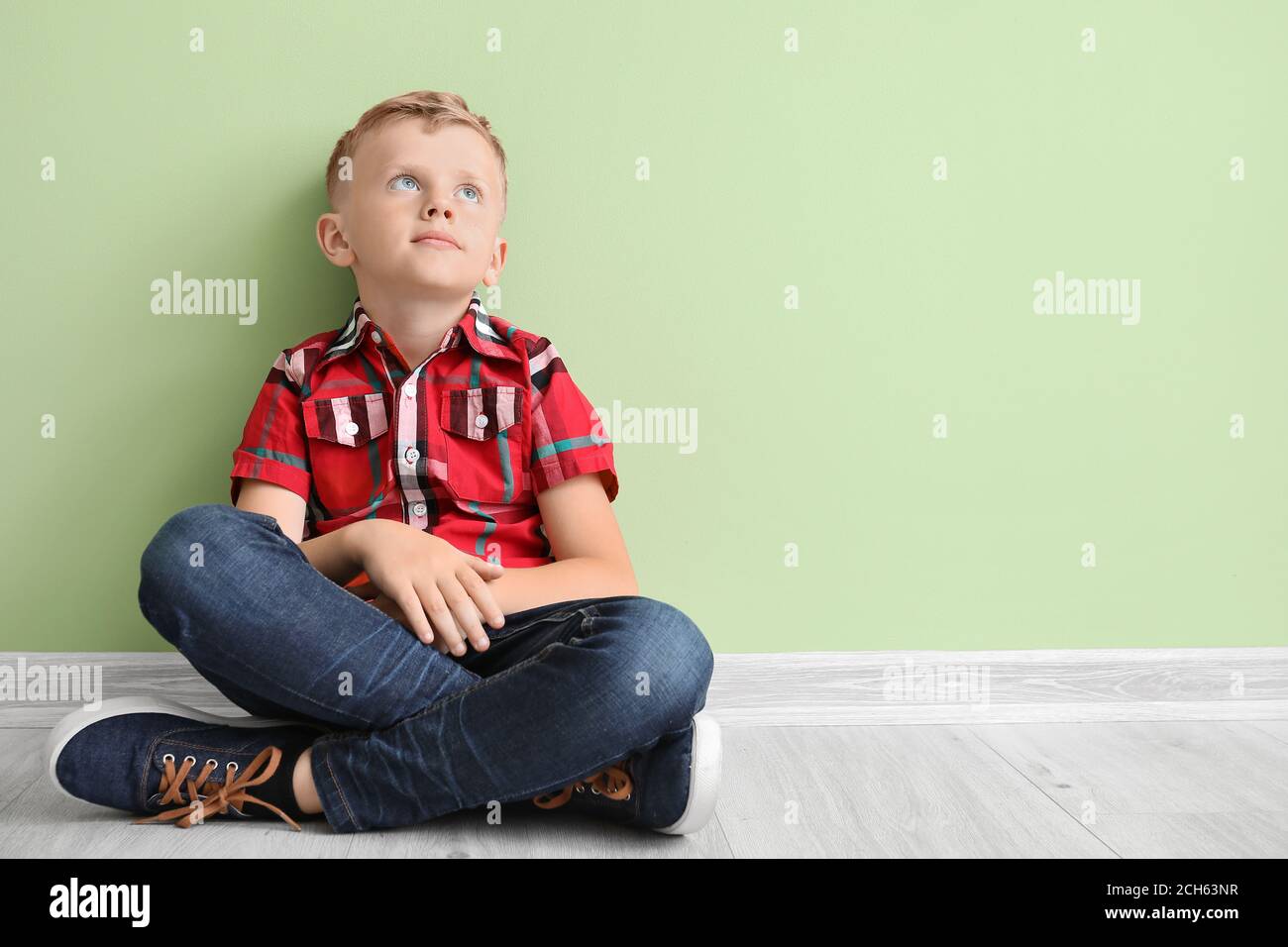 Little boy with autistic disorder sitting near color wall Stock Photo ...