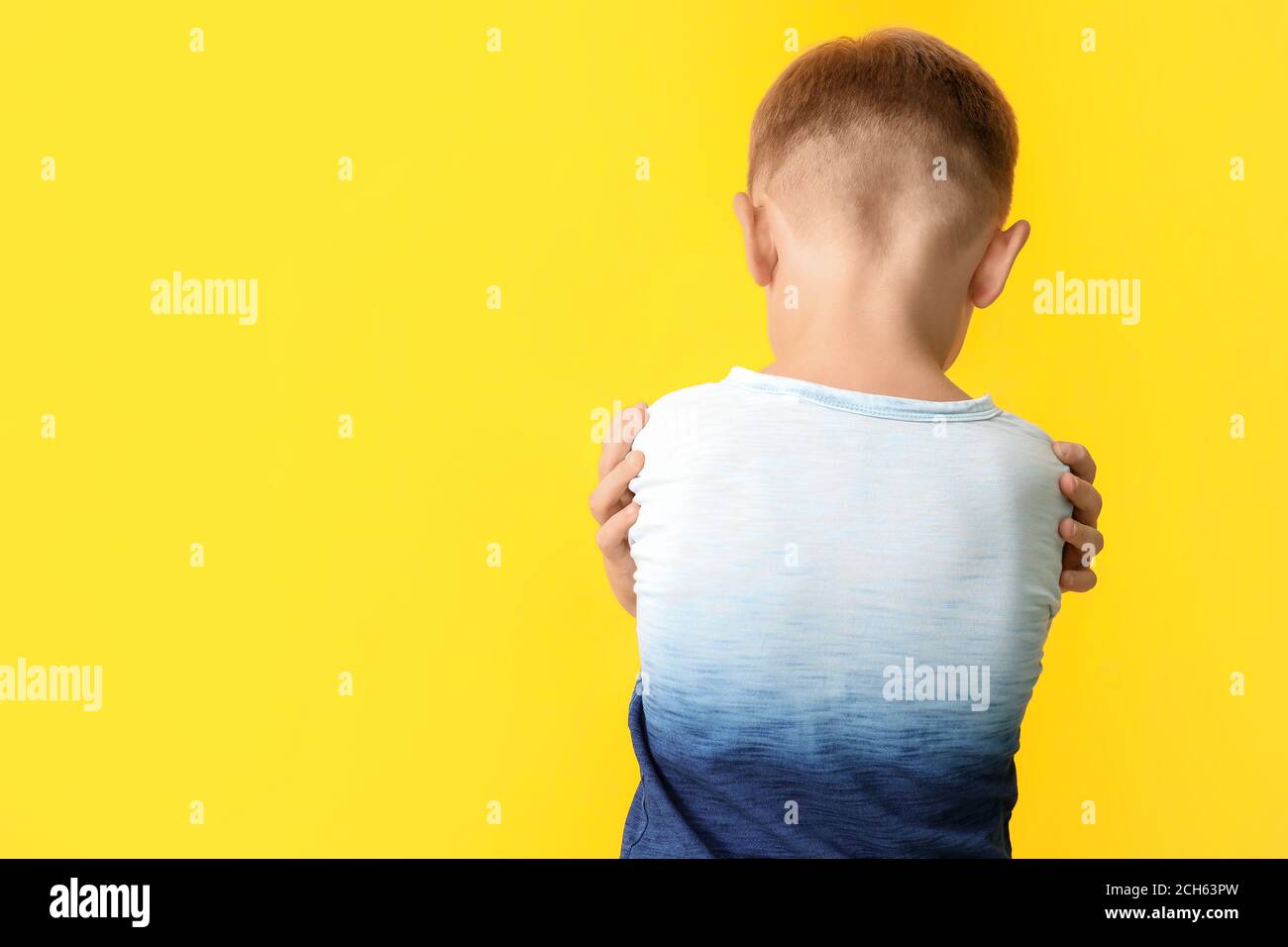 Sad little boy with autistic disorder on color background, back view ...