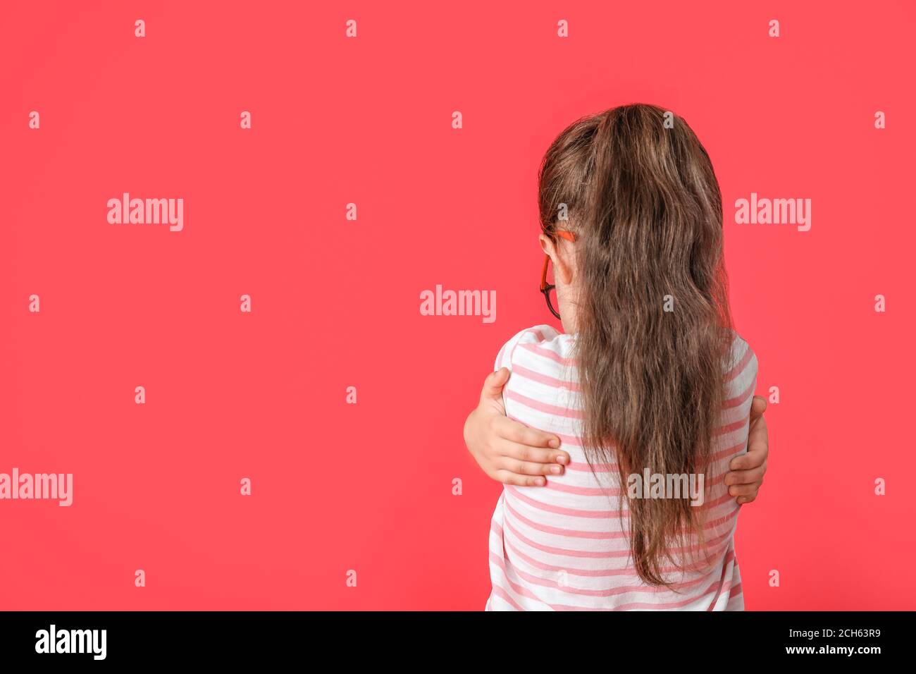 Sad little girl with autistic disorder on color background, back view ...