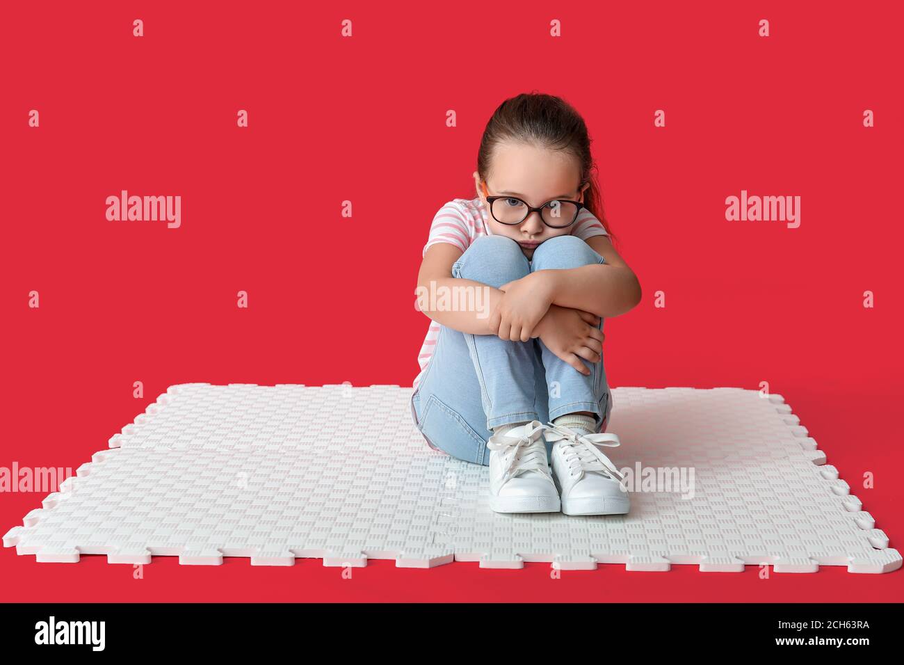 Sad little girl with autistic disorder on color background Stock Photo ...