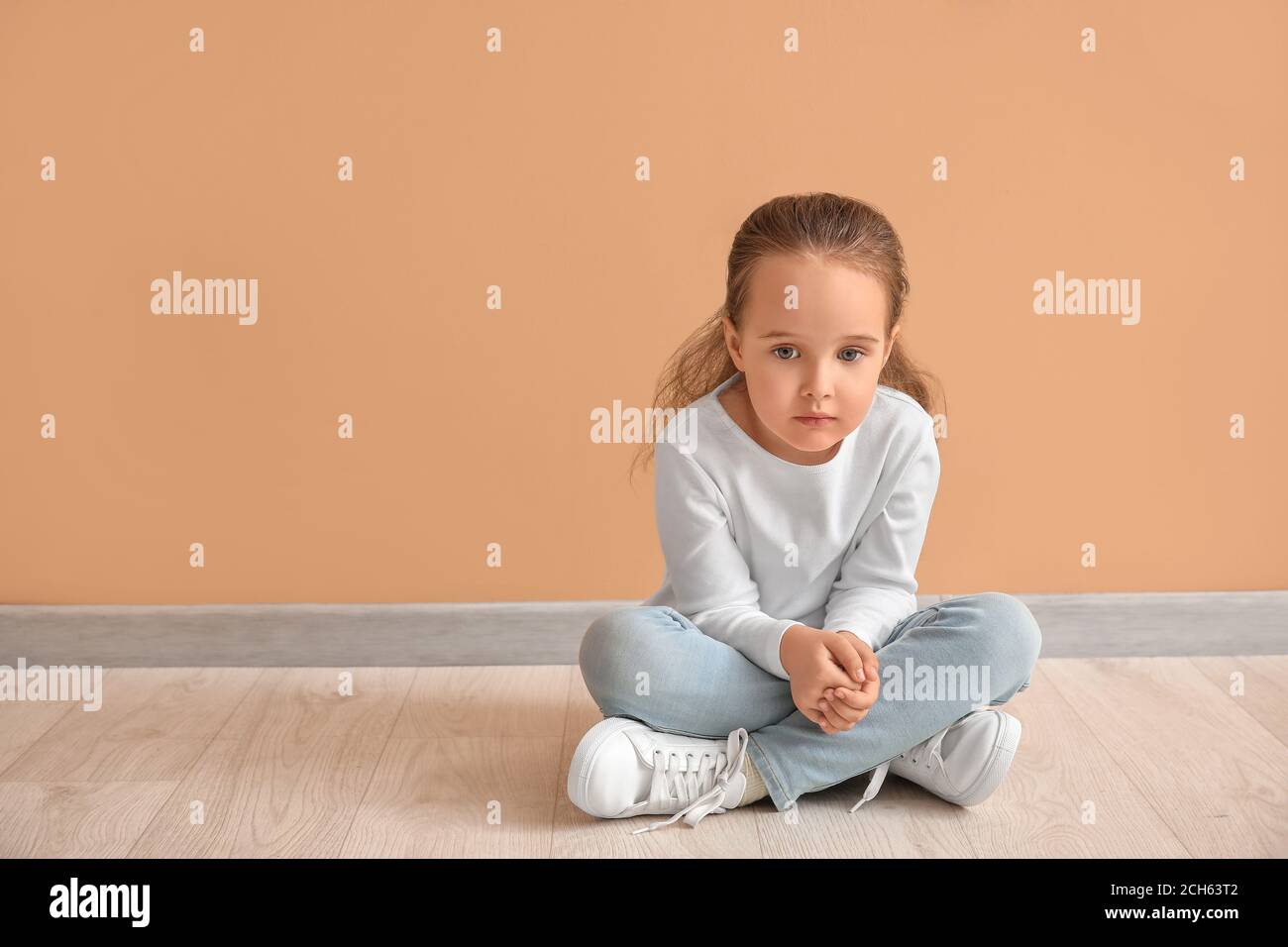 Sad little girl with autistic disorder sitting near color wall Stock ...