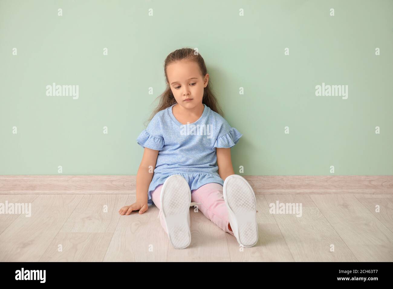 Sad little girl with autistic disorder sitting near color wall Stock ...