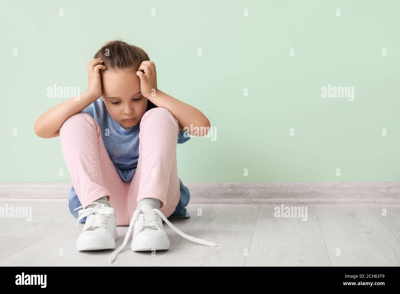 Little girl with autistic disorder sitting near color wall Stock Photo ...