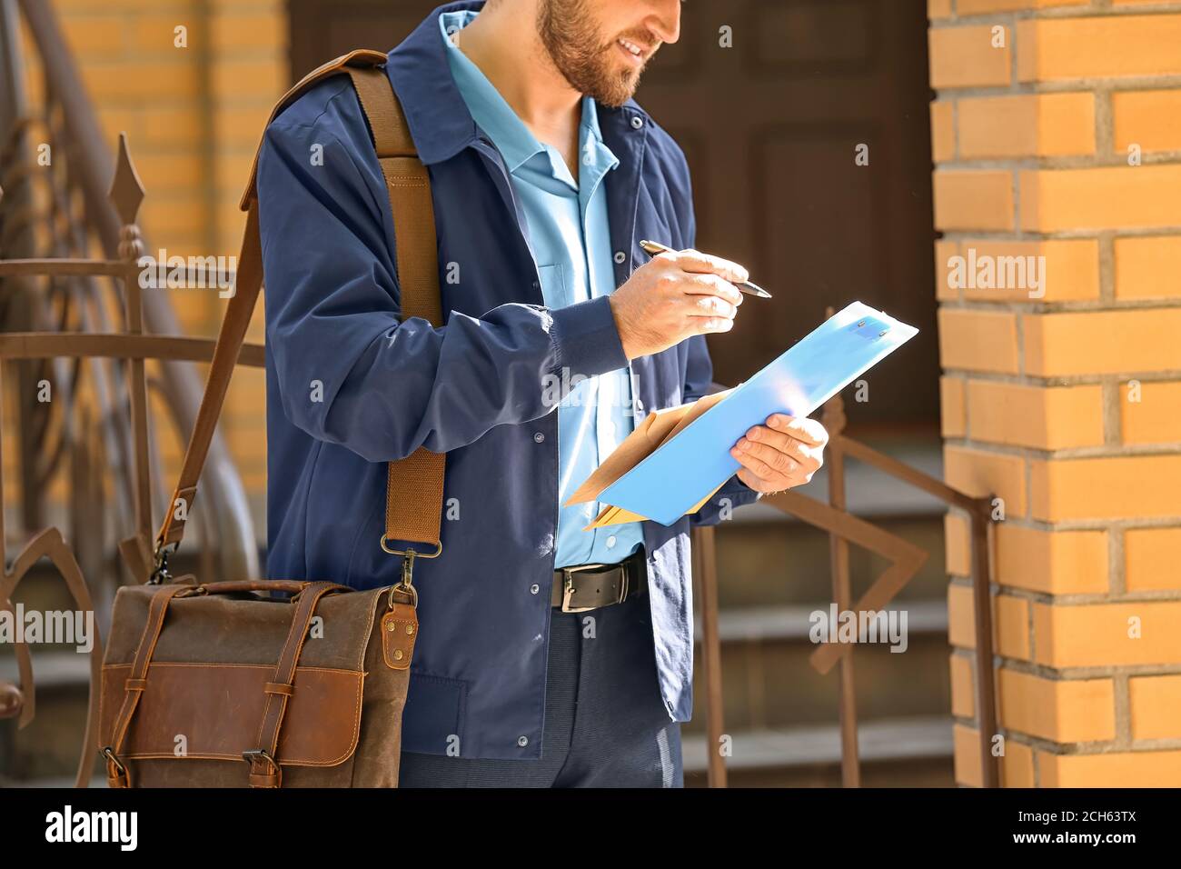 Handsome young postman with letters outdoors Stock Photo - Alamy