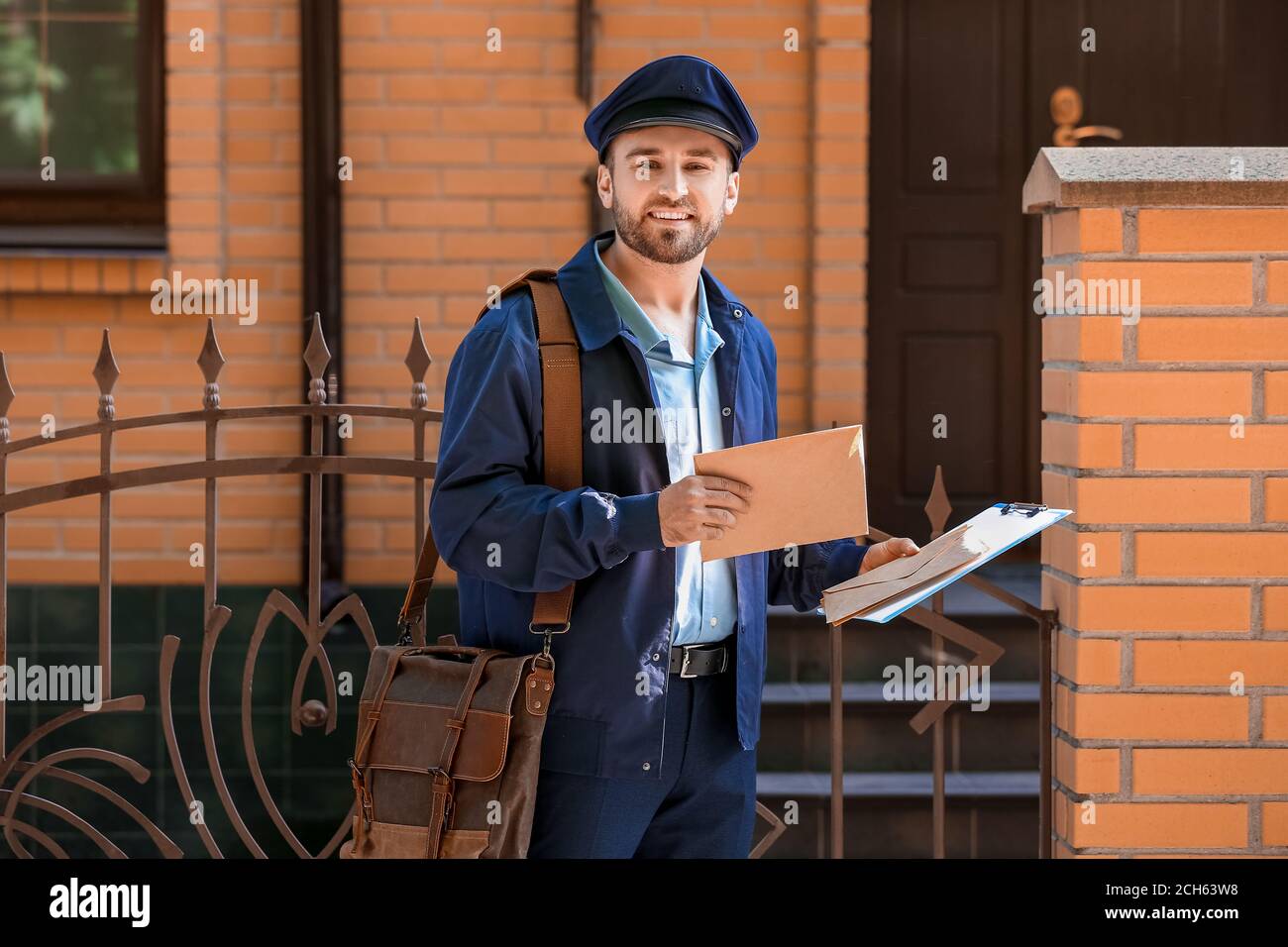 Handsome young postman with letters outdoors Stock Photo - Alamy