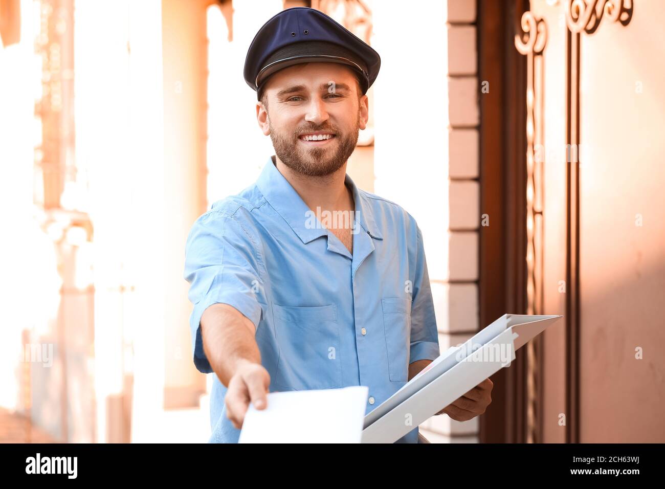 Handsome young postman with letters outdoors Stock Photo - Alamy