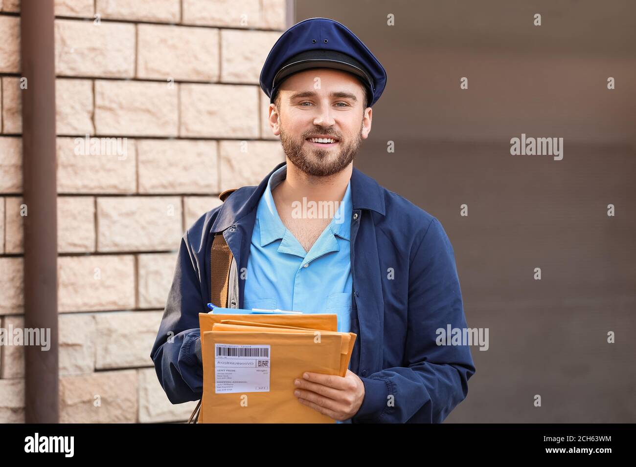 Handsome young postman with letters outdoors Stock Photo - Alamy