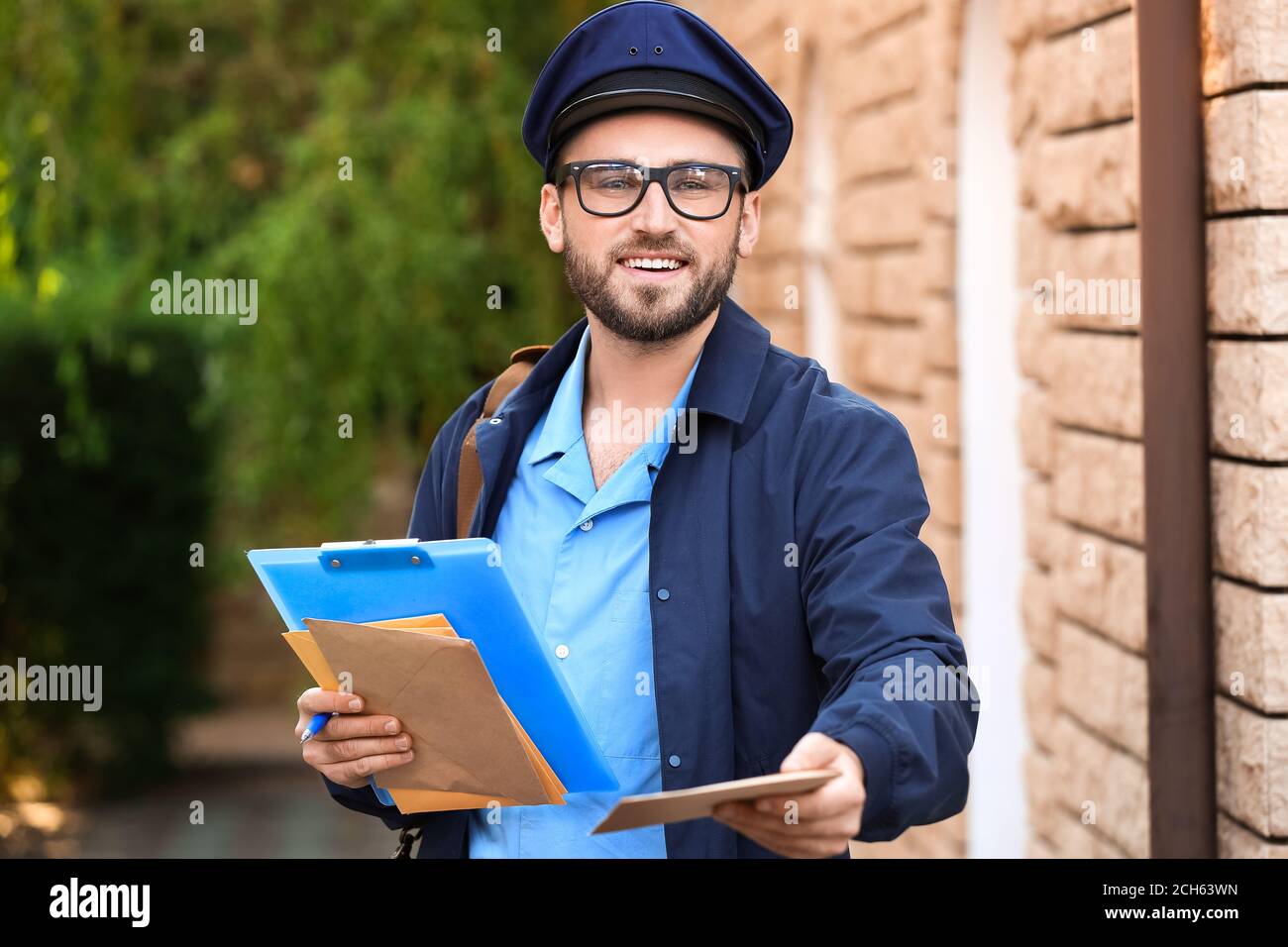 Handsome young postman with letters outdoors Stock Photo - Alamy