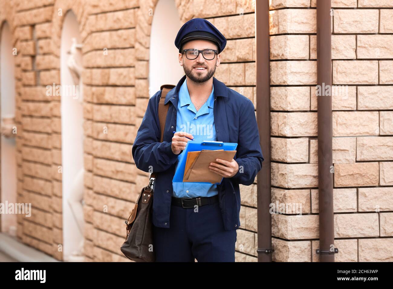 Handsome young postman with letters outdoors Stock Photo - Alamy