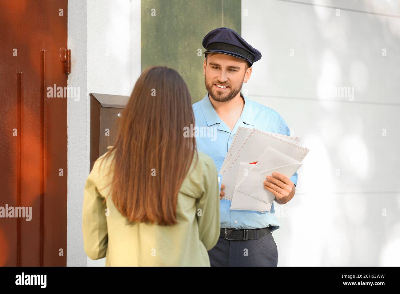 Woman receiving letter from postman outdoors Stock Photo - Alamy