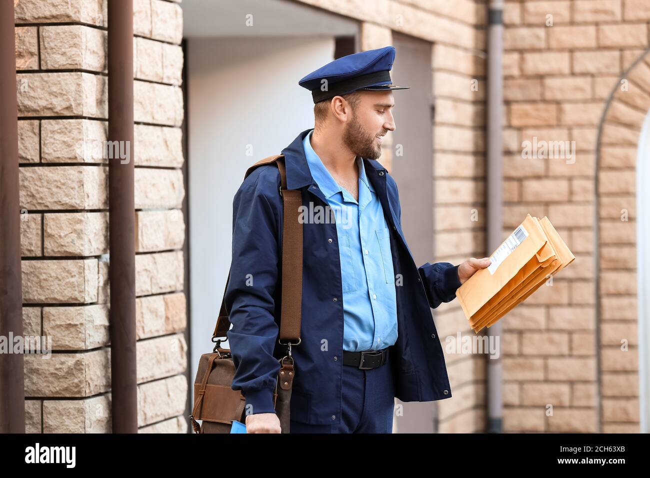 Handsome young postman with letters outdoors Stock Photo - Alamy
