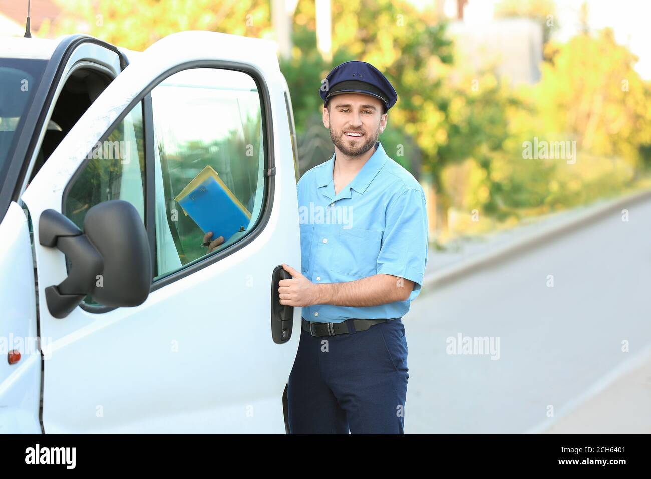 Handsome young postman getting in car outdoors Stock Photo - Alamy