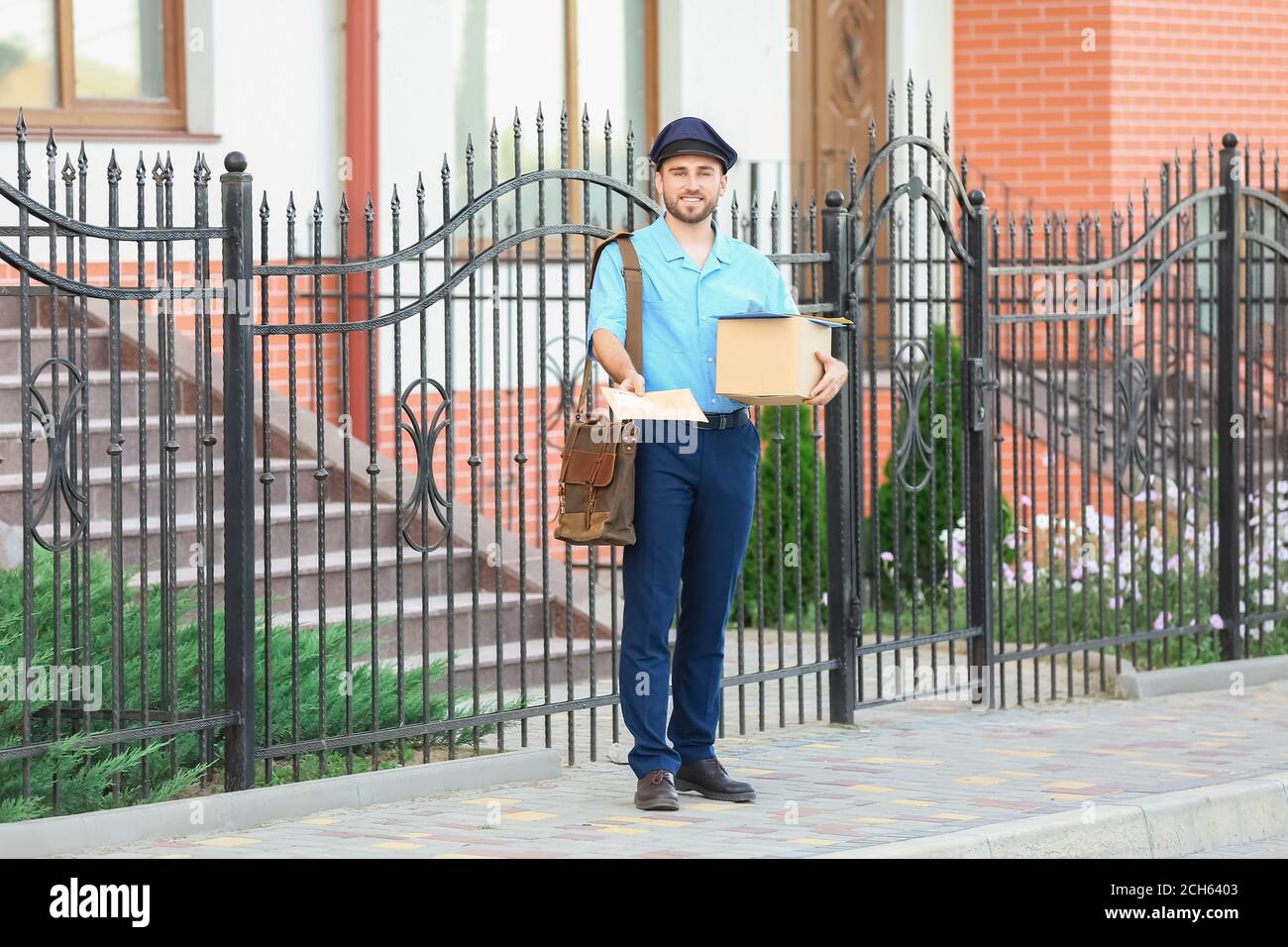 Handsome young postman with parcel outdoors Stock Photo - Alamy
