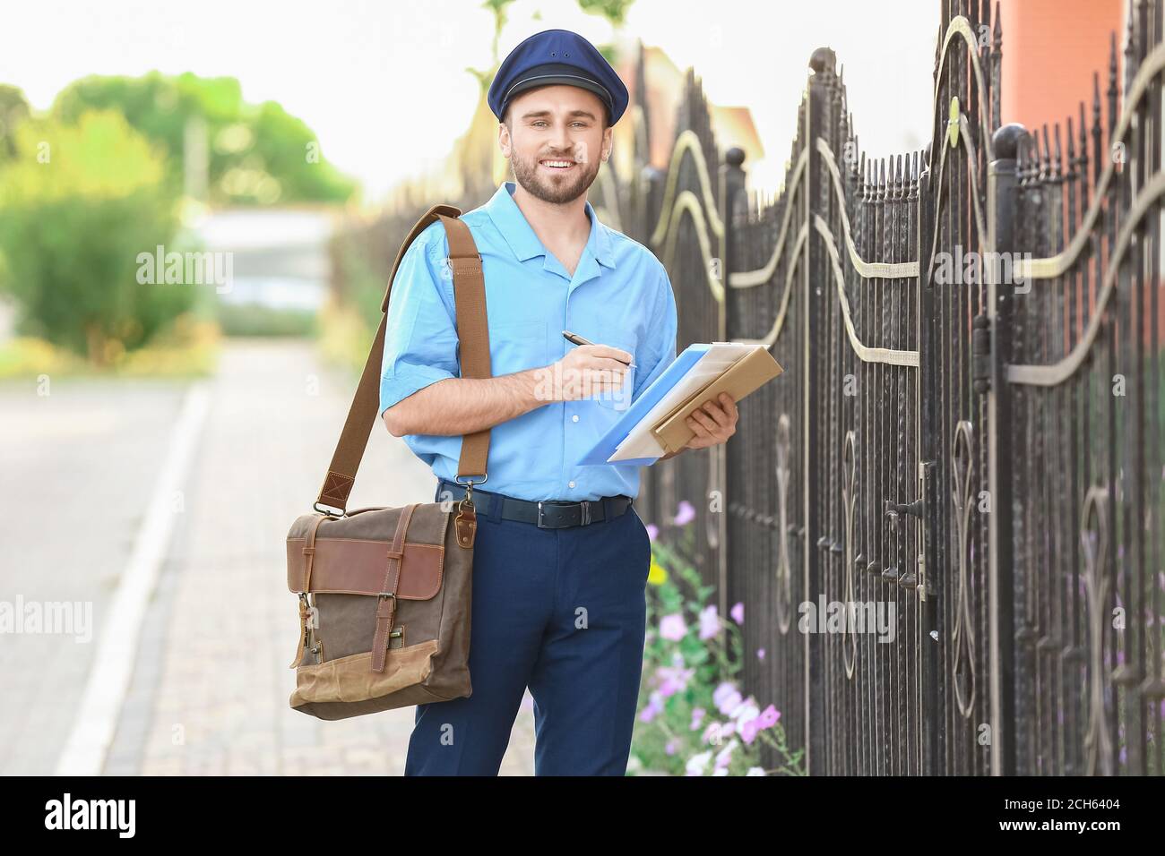 Handsome young postman with letters outdoors Stock Photo - Alamy
