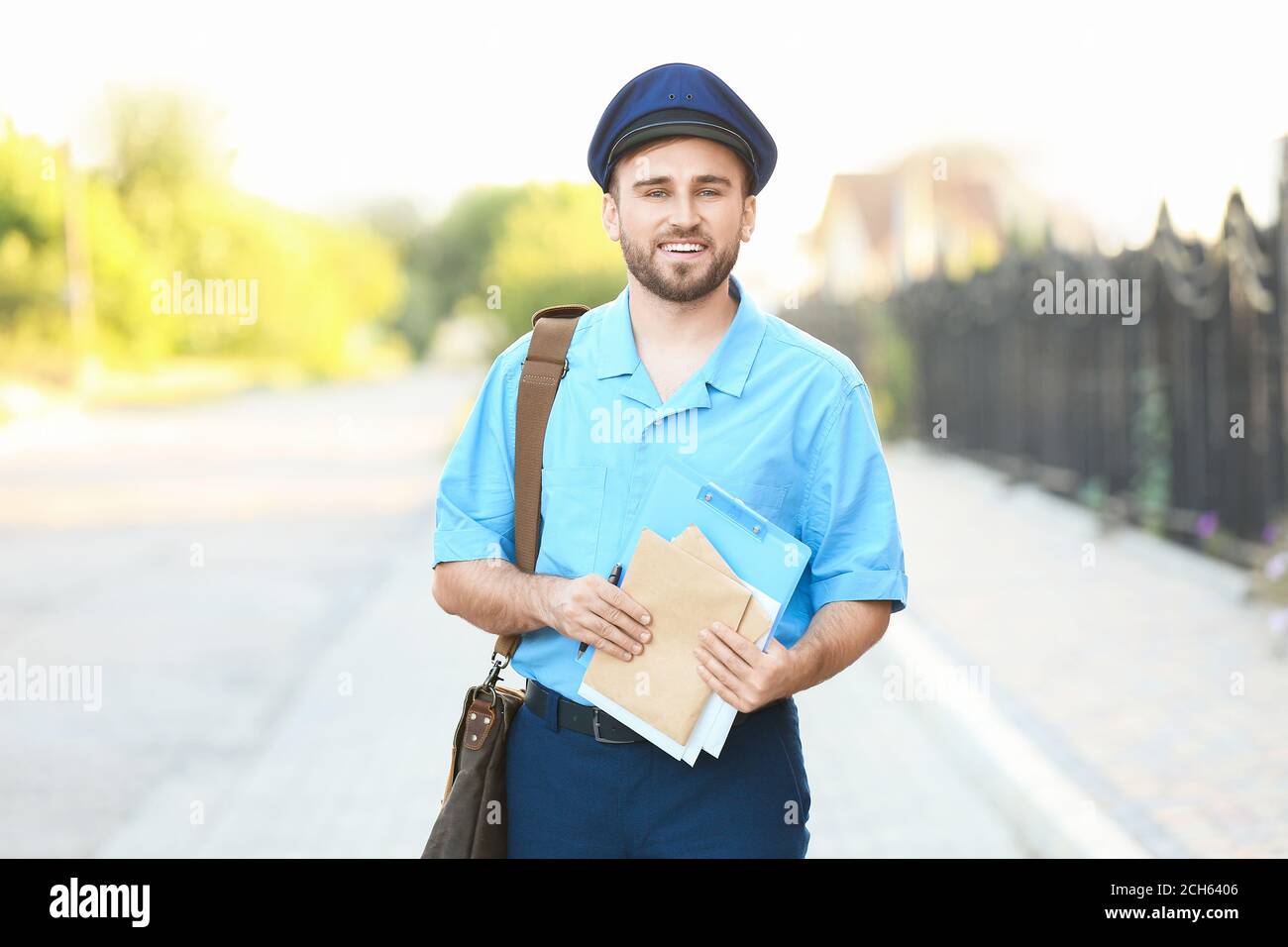 Handsome young postman with letters outdoors Stock Photo - Alamy