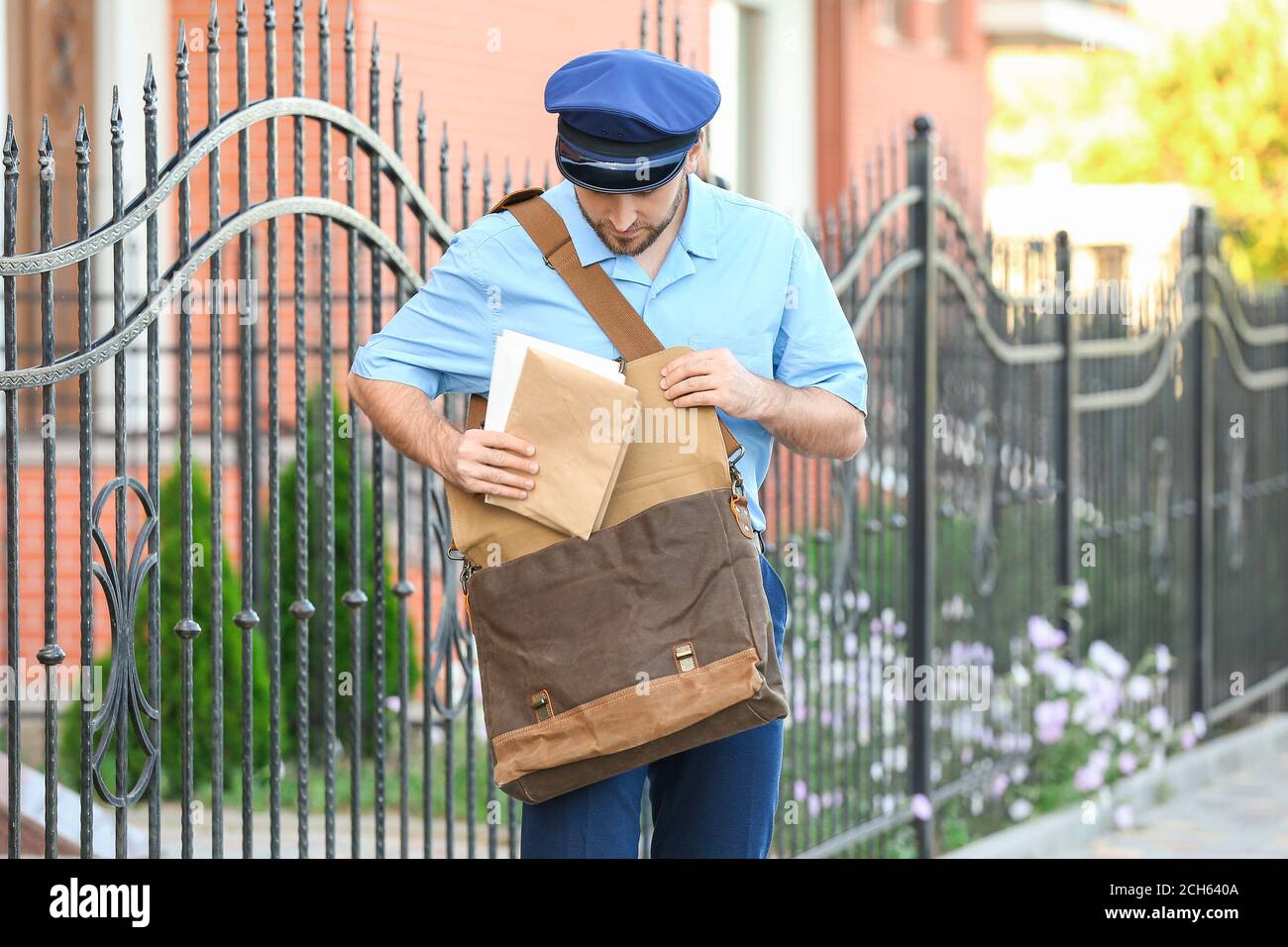 Handsome young postman with letters outdoors Stock Photo - Alamy