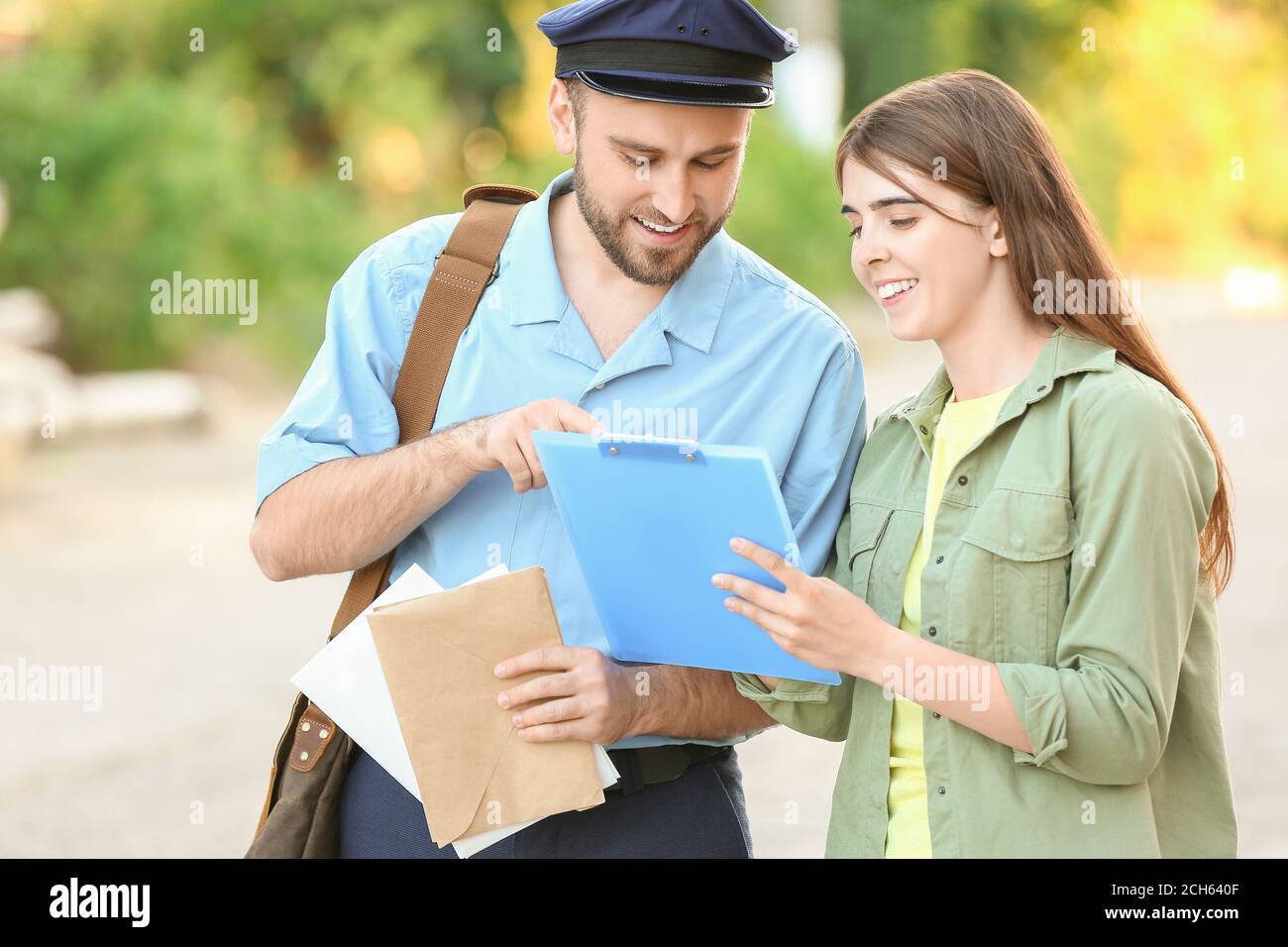Woman receiving parcel from postman outdoors Stock Photo - Alamy