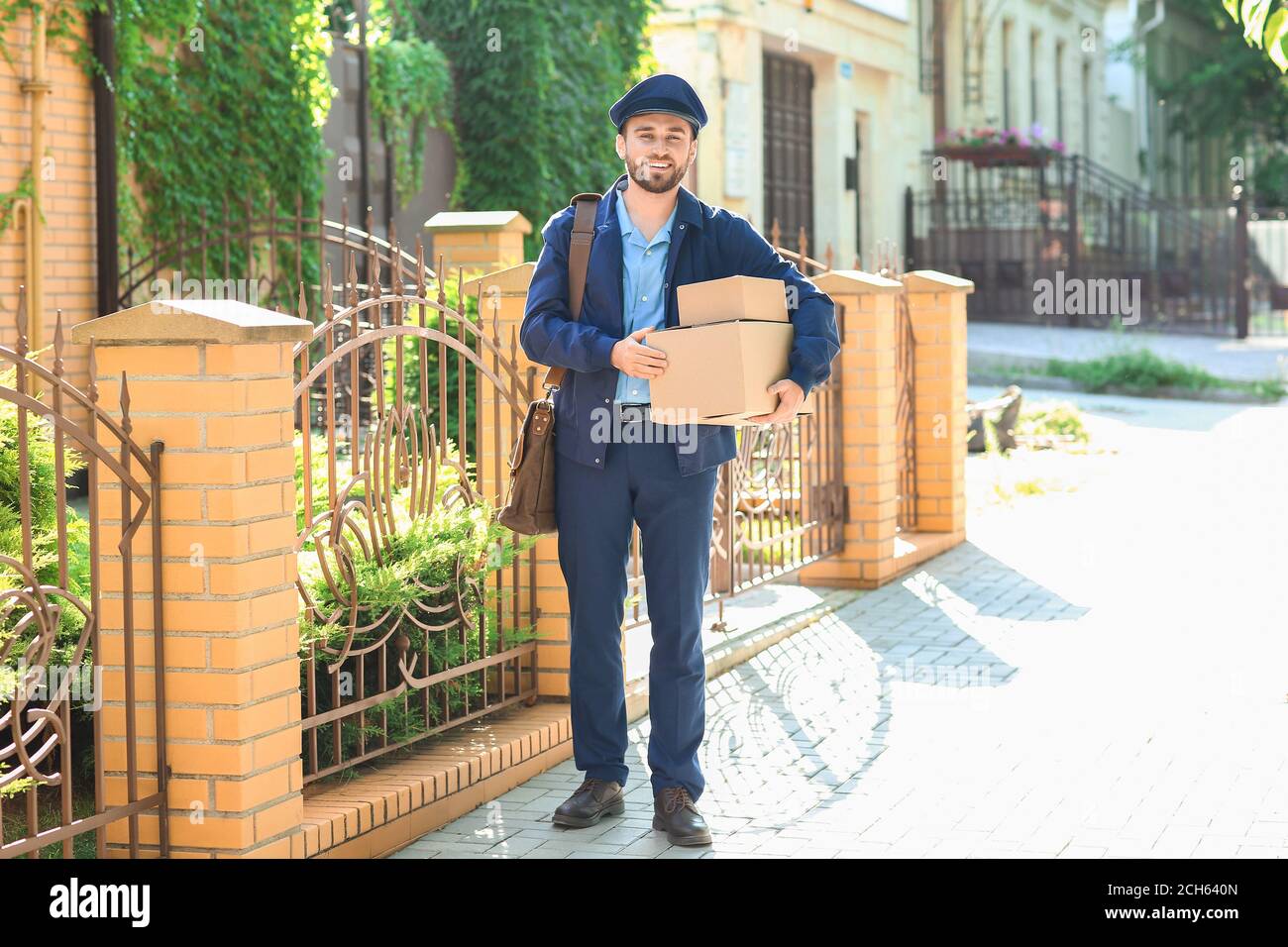 Handsome young postman with parcels outdoors Stock Photo - Alamy