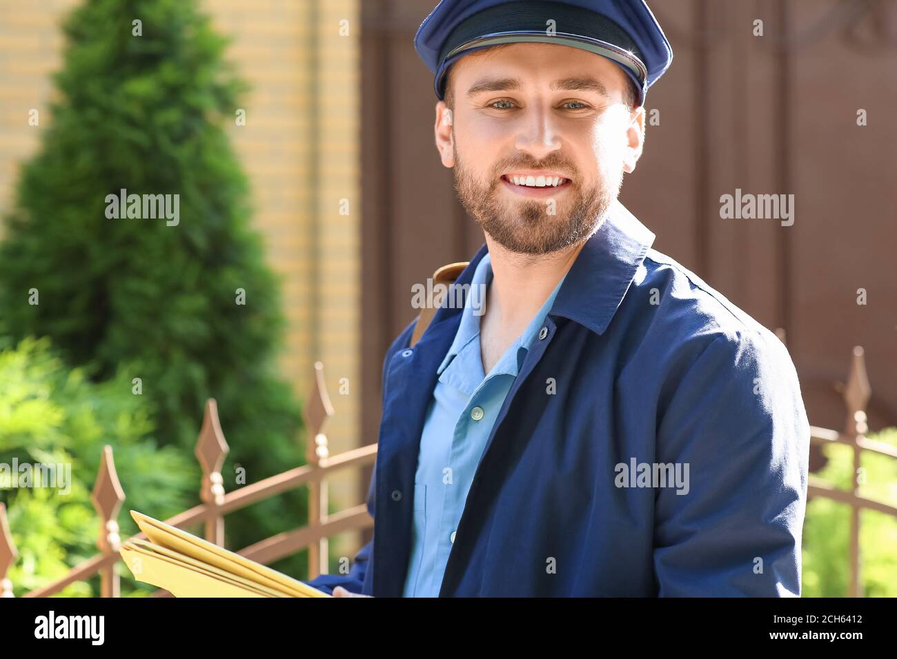 Handsome young postman with letters outdoors Stock Photo - Alamy