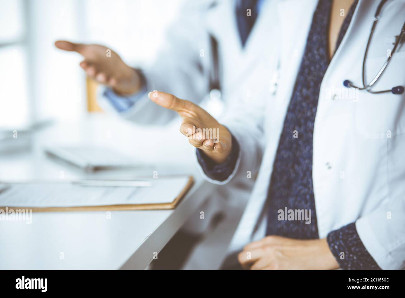 Two doctors sitting and offering helping hand for shaking hand or ...