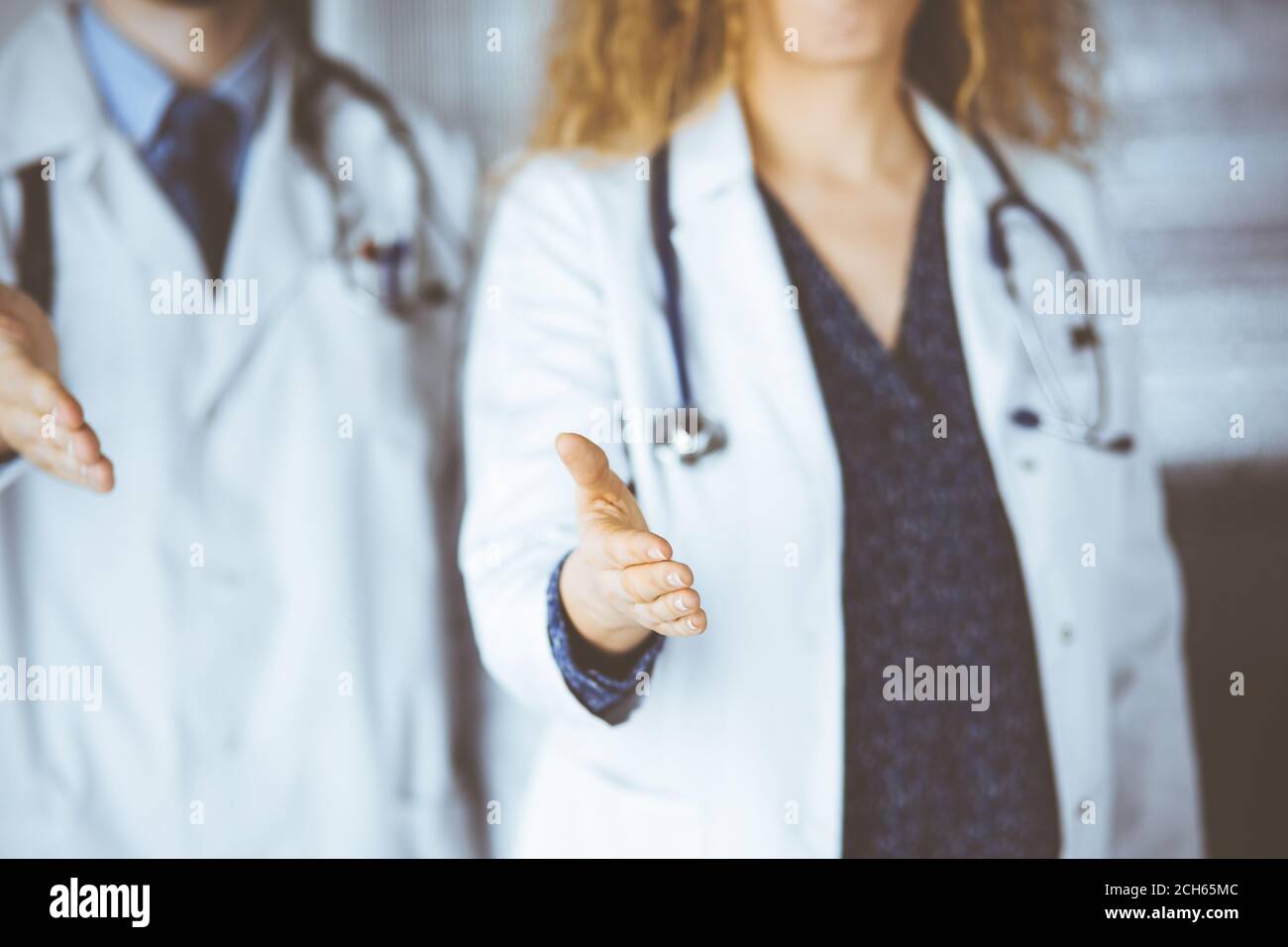 Two doctors standing and offering helping hand for shaking hand or ...