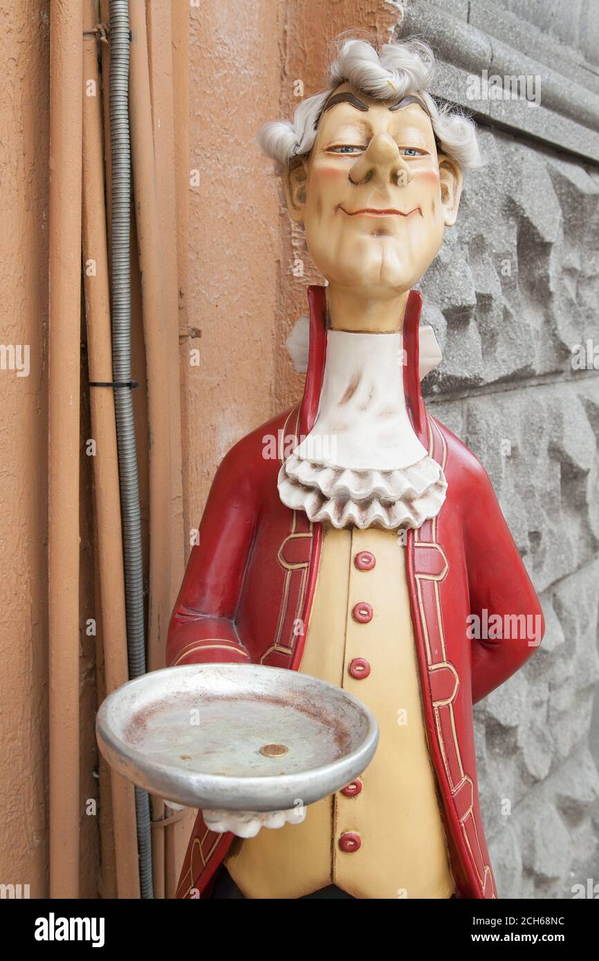 Old-style British waiter statue outdoors with plate for coin tips Stock ...