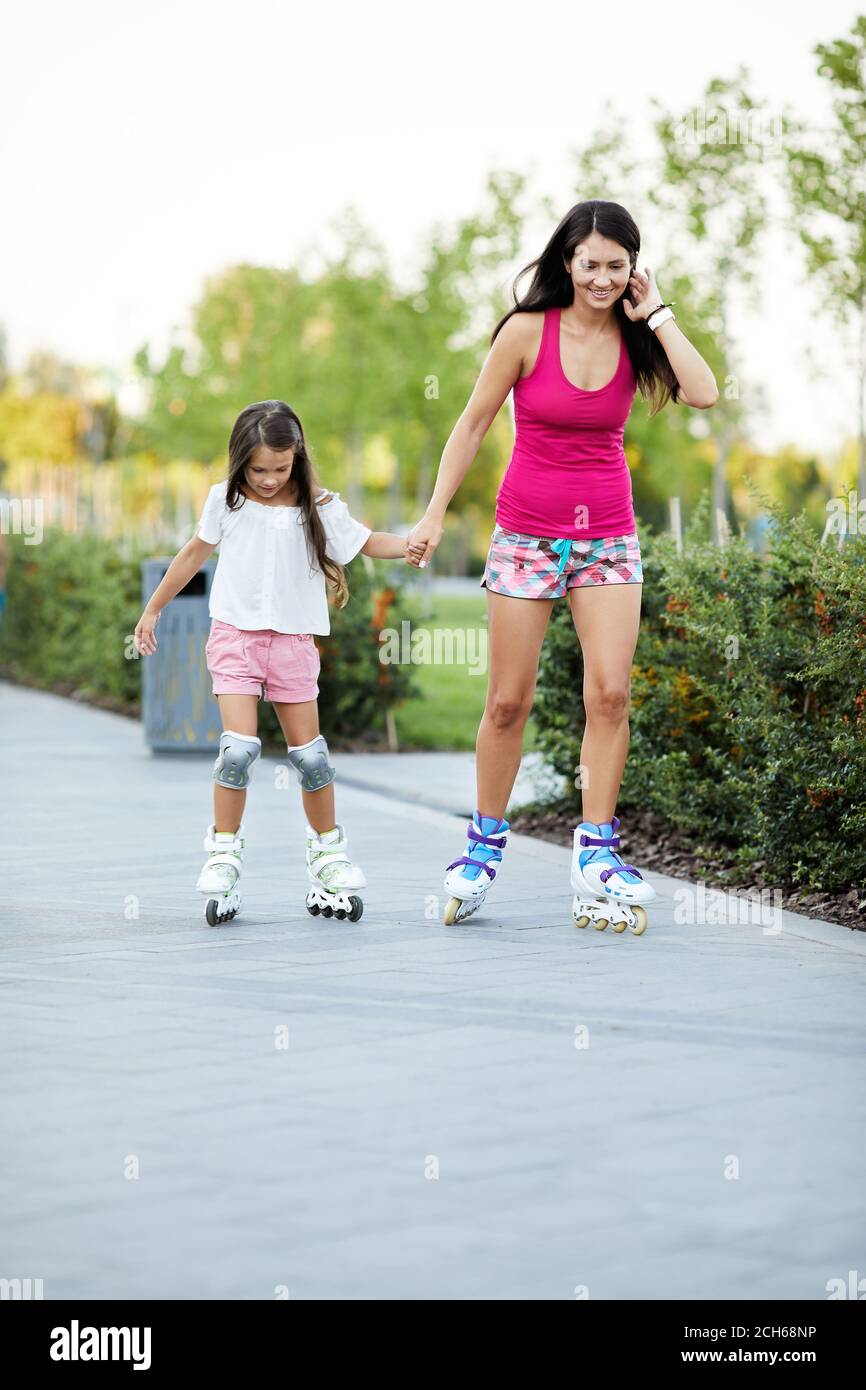 happy mother and her little daughter rollerskating in summer park Stock Photo - Alamy