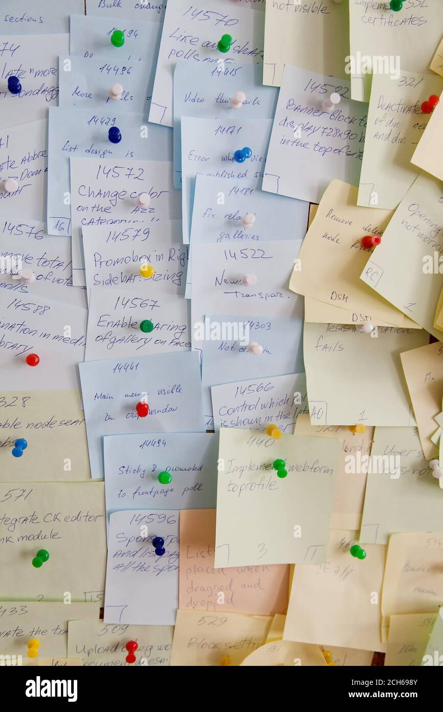 Bunch of pinned paper tickets on kanban with tasks and selective focus ...