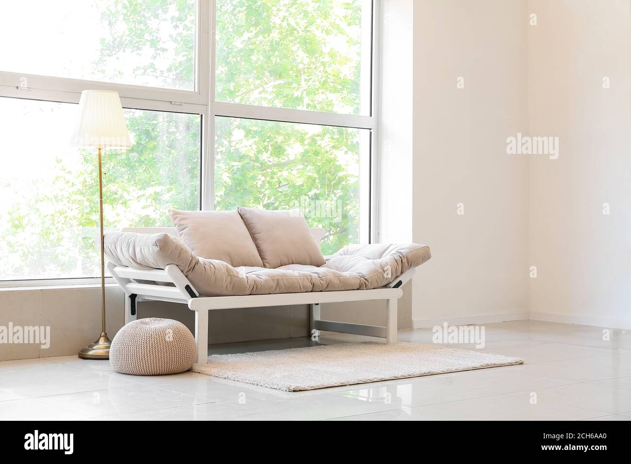 Stylish modern sofa near window in room Stock Photo - Alamy