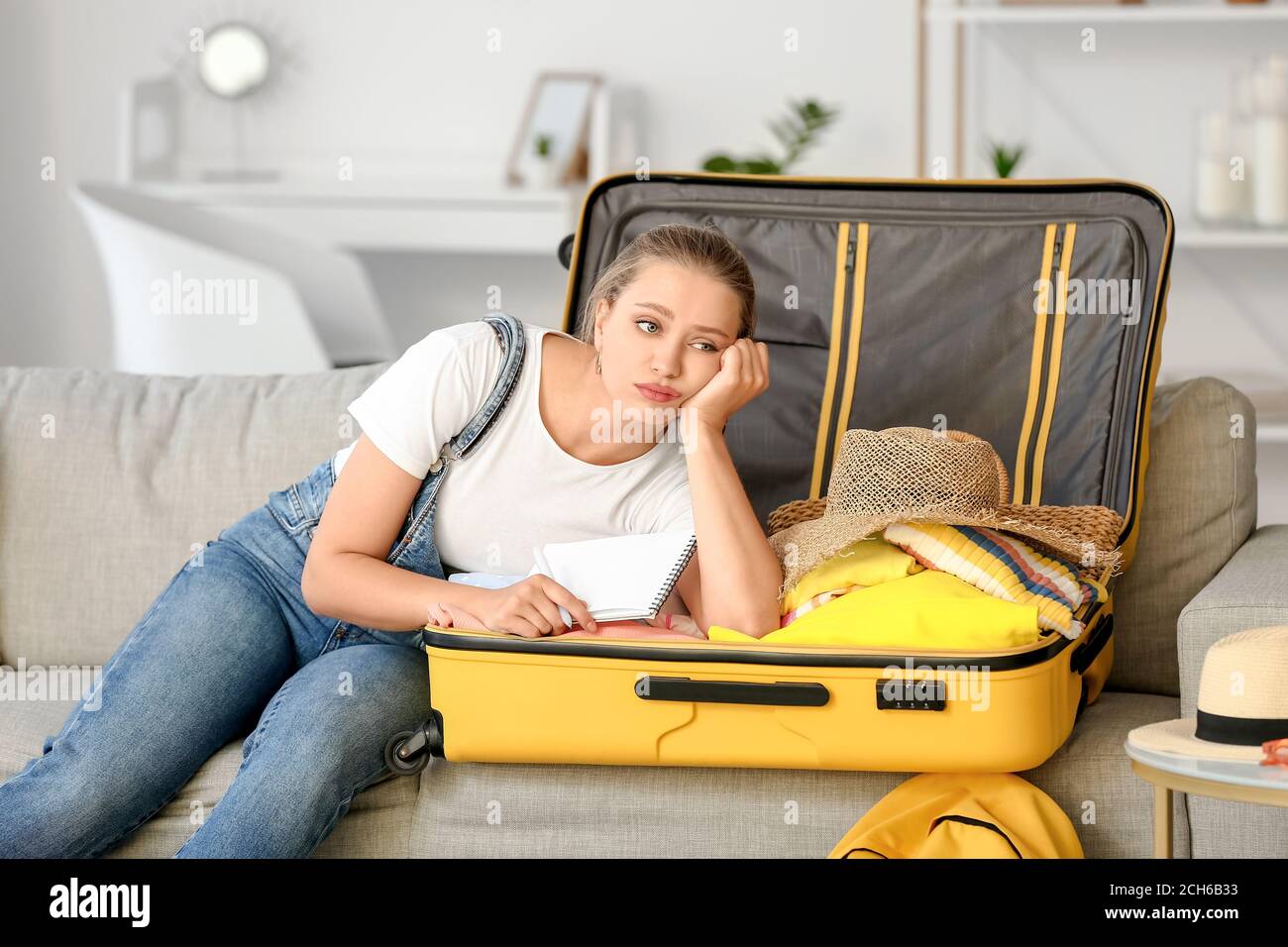 Sad young woman packing suitcase at home. Travel concept Stock Photo ...