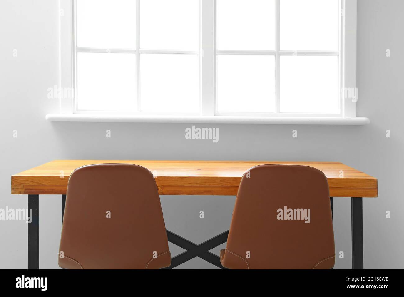 Table and chairs near wall with window Stock Photo - Alamy