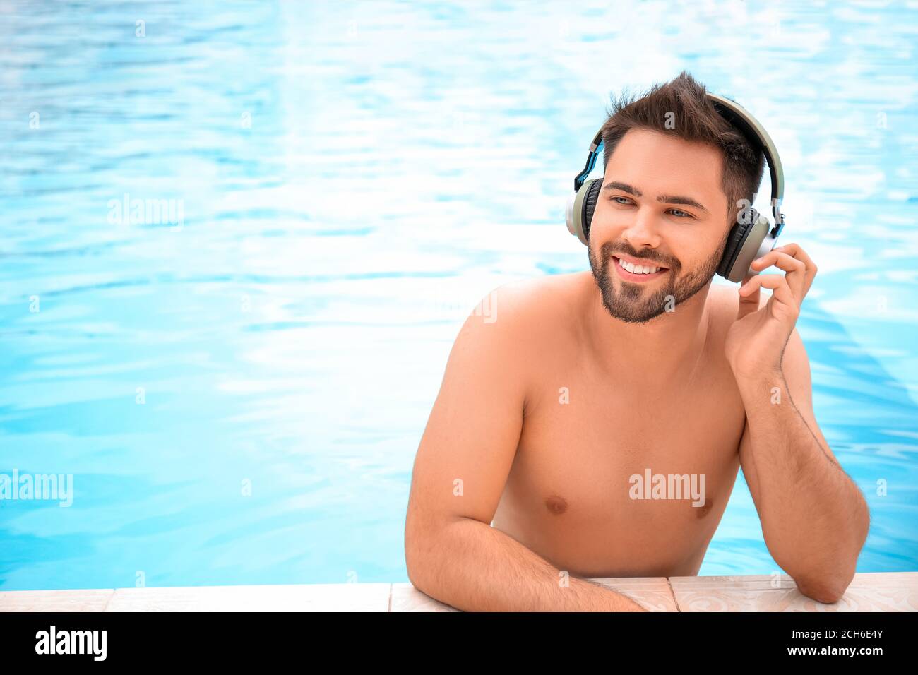 Young man listening to music in swimming pool Stock Photo - Alamy